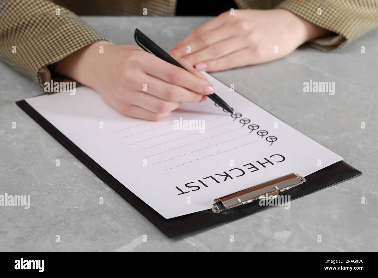 Woman filling Checklist at grey marble table, closeup Stock Photo - Alamy