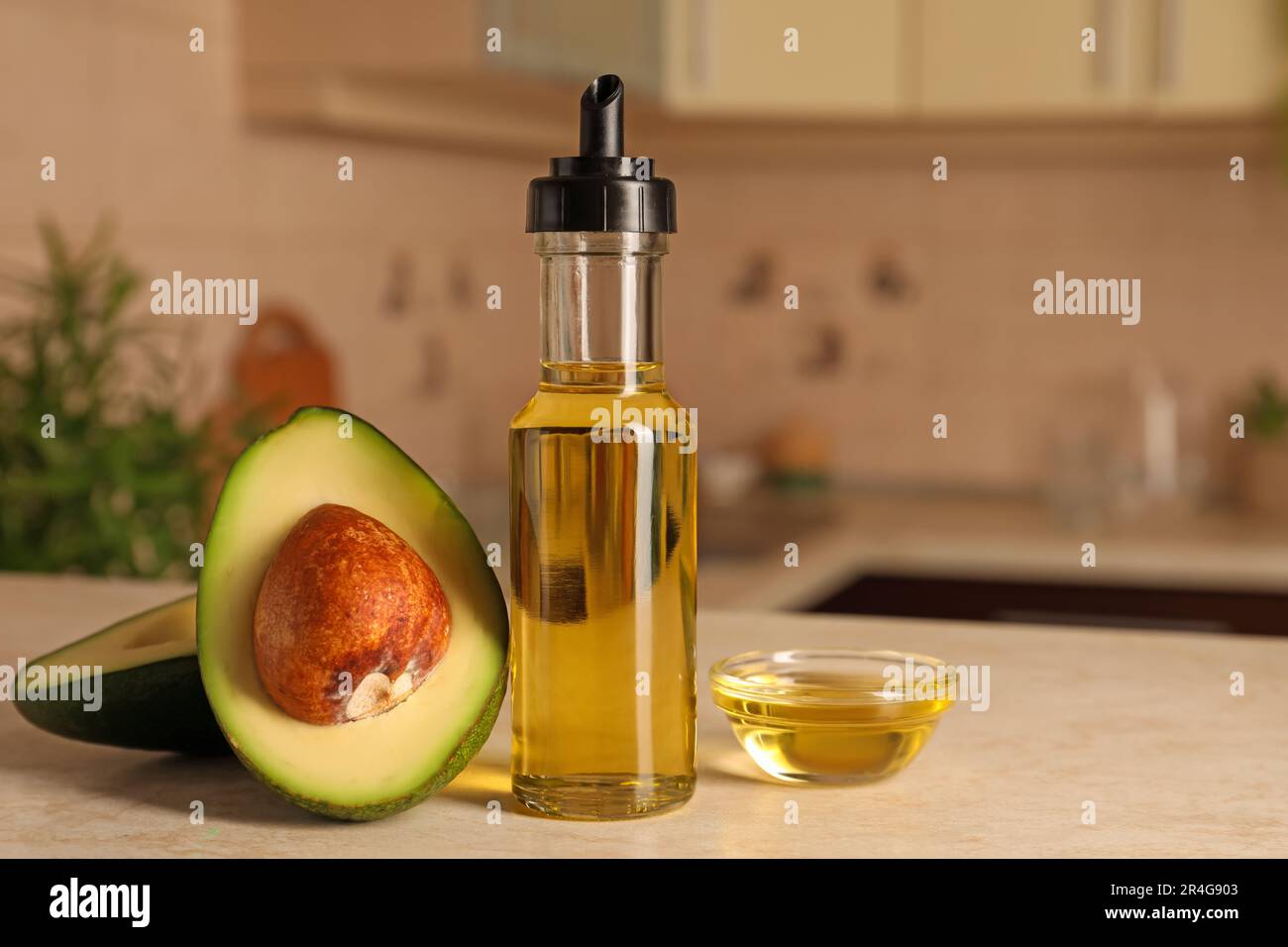 Fresh avocado and cooking oil on beige marble table in kitchen, space ...