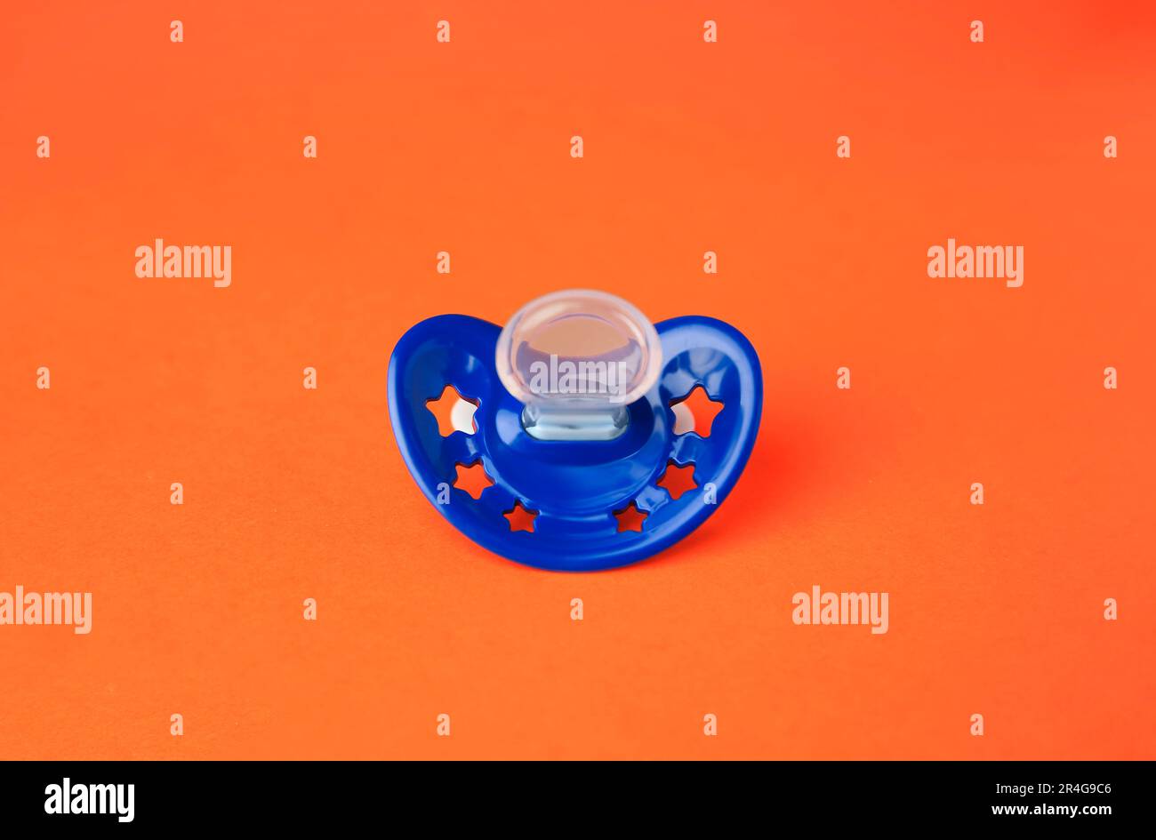 One blue baby pacifier on orange background Stock Photo - Alamy