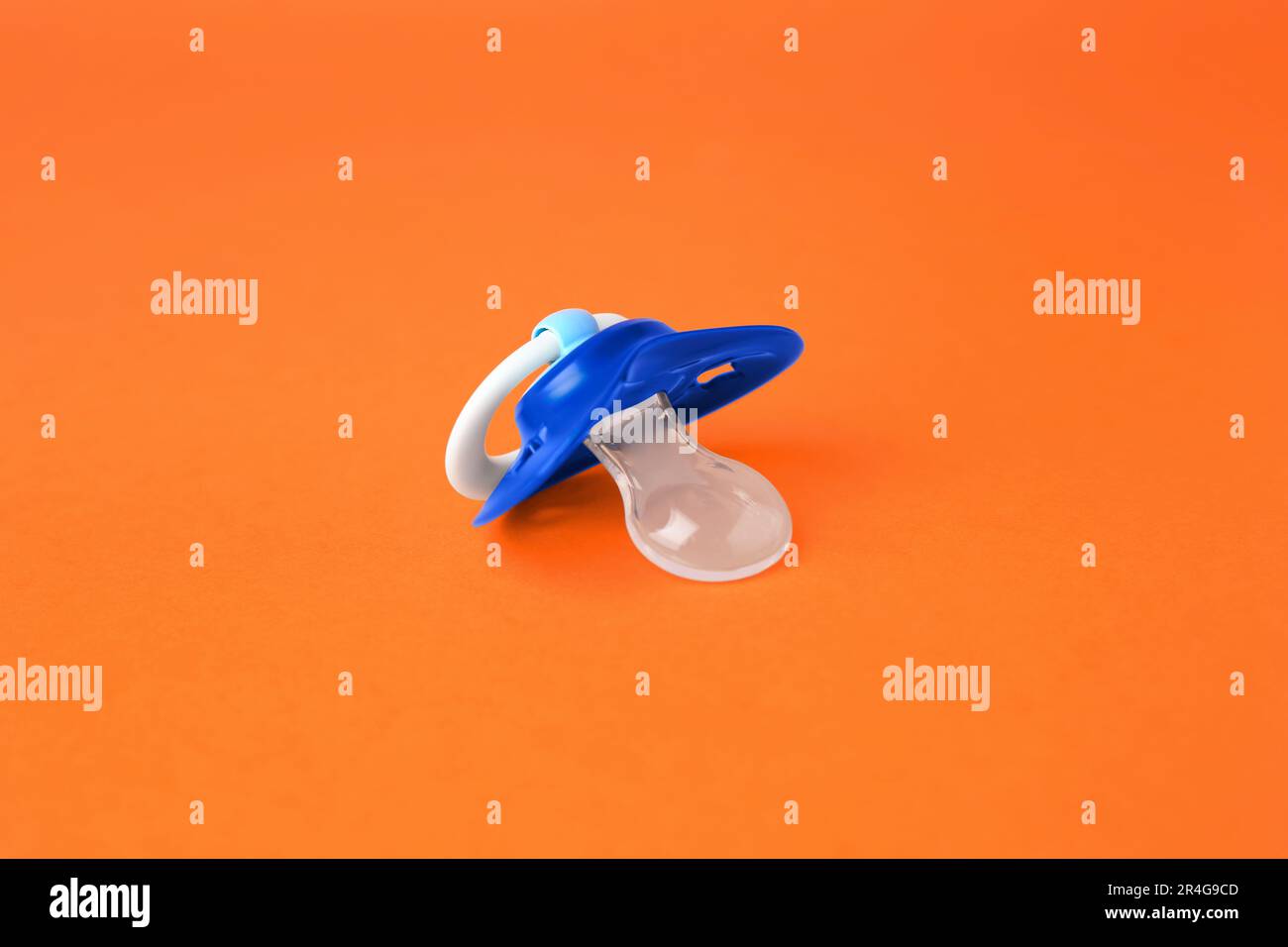One blue baby pacifier on orange background Stock Photo - Alamy