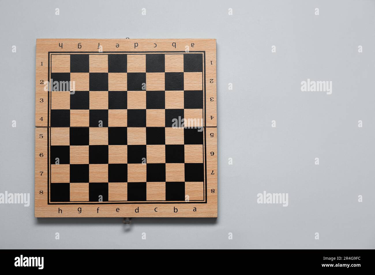 Empty wooden checkerboard on light grey background, top view. Space for ...