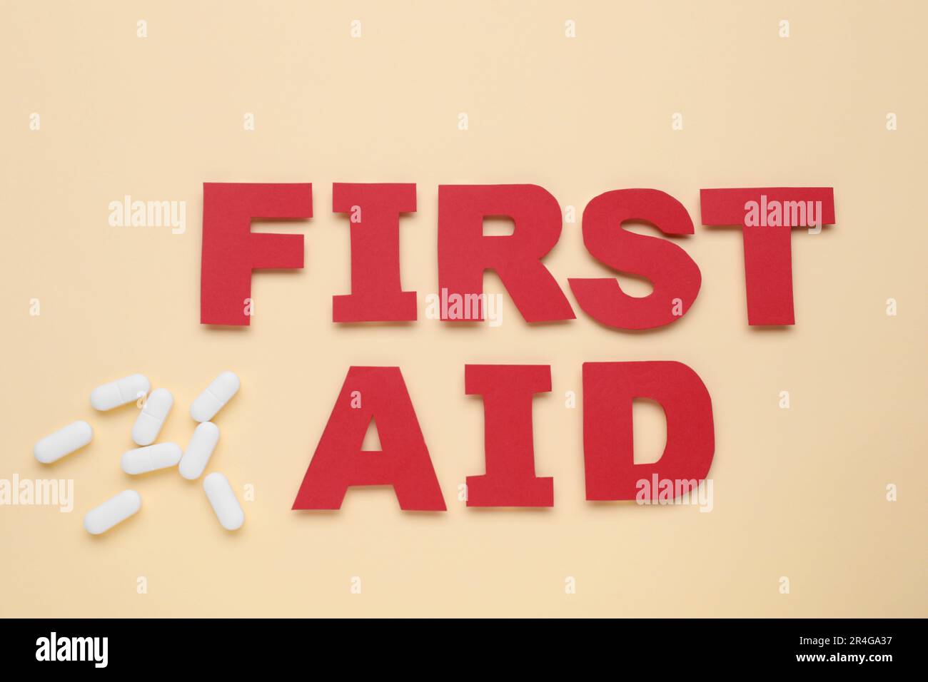 Words First Aid made of red letters and pills on beige background, flat ...