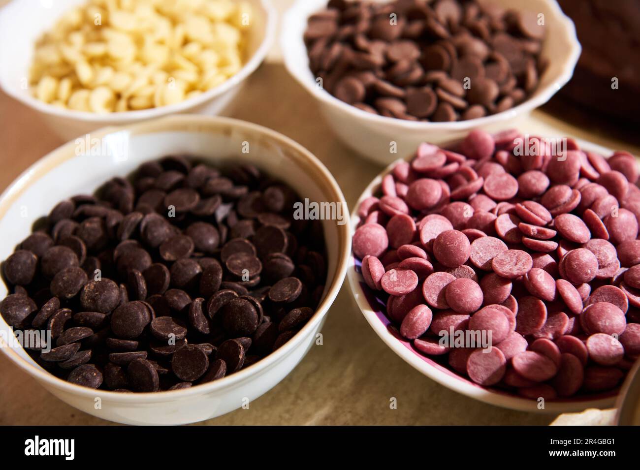 Dark, milk, white and ruby pink chocolate chips in bowls on marble ...