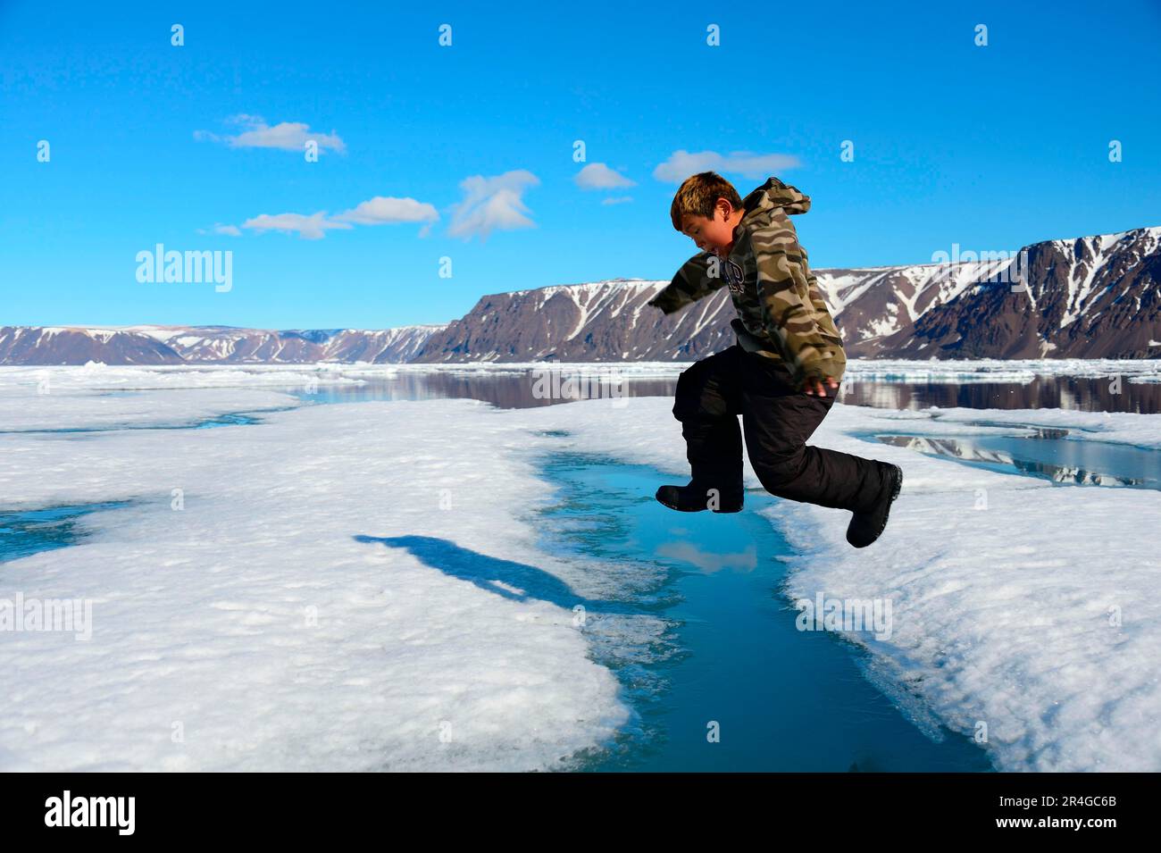 Inuit boy jumps over crevasse in ice floe, Ellesmer, Eskimo, Inuit boy ...