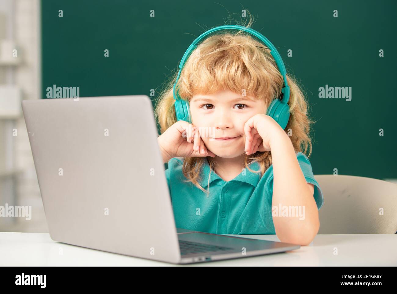 Clever school boy, cute pupil wears headphones writing on laptop, listen audio lesson use ...