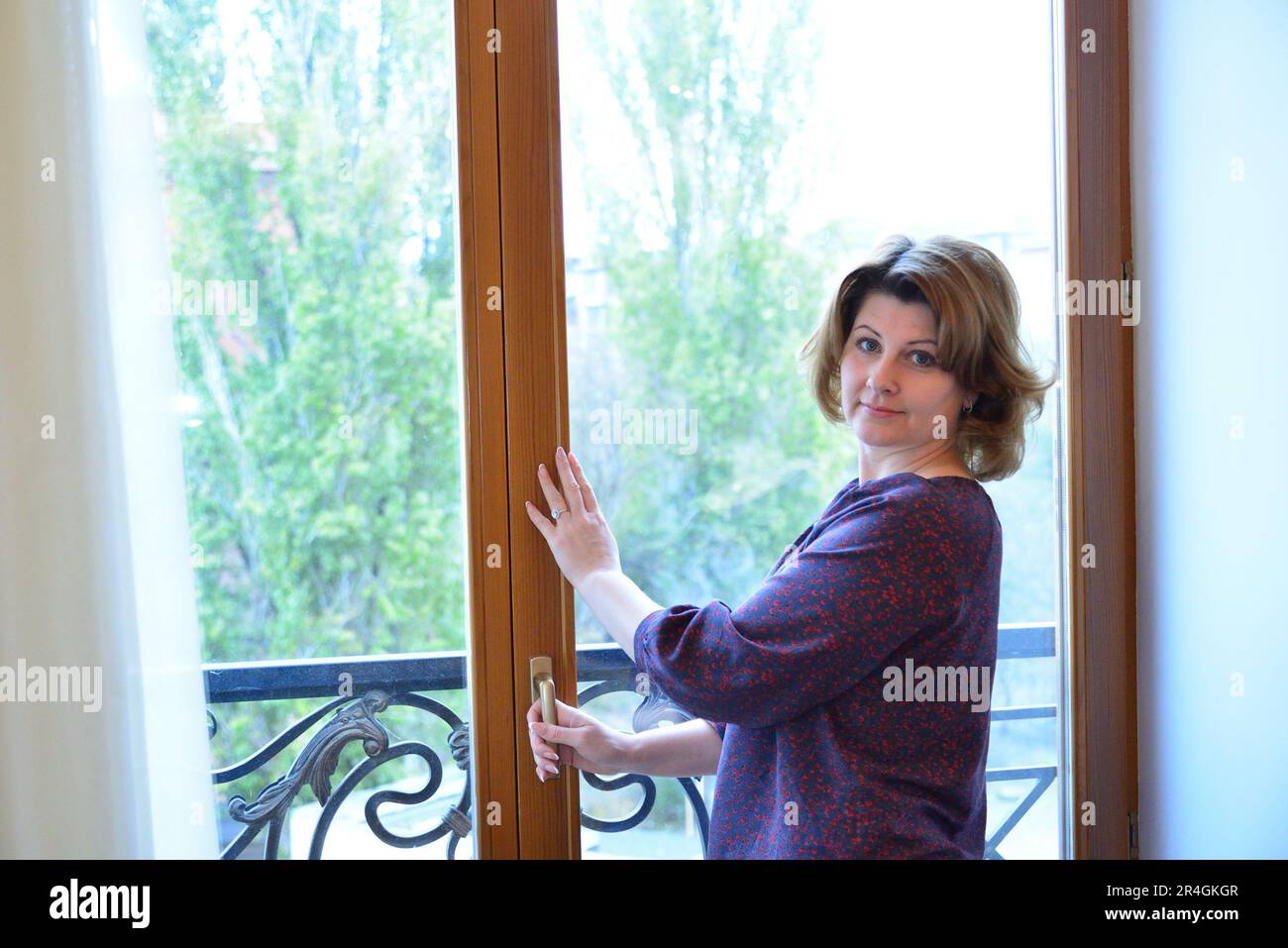 Woman opens or closes window to the balcony Stock Photo - Alamy