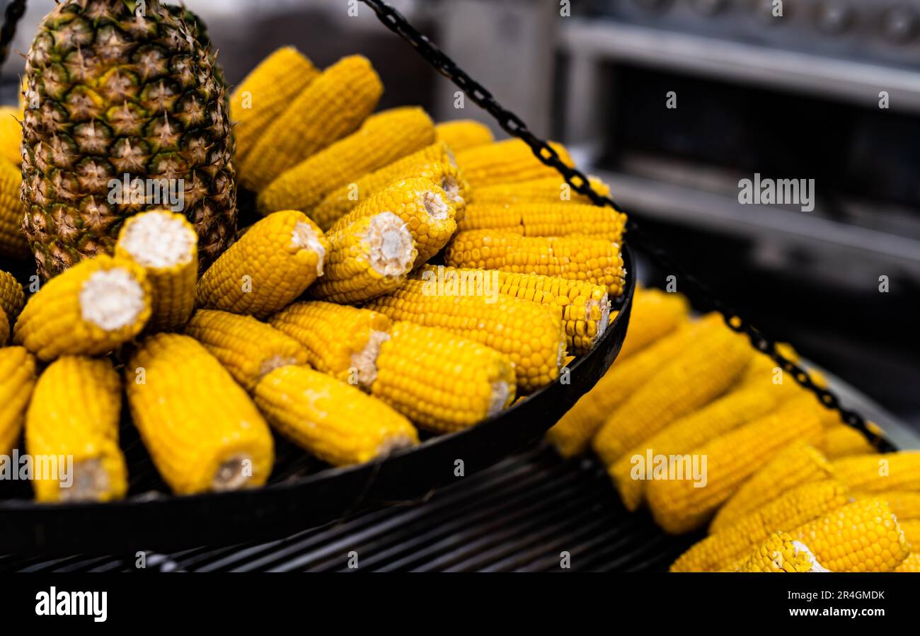 Boiled corn and pineapple at street food market closeup. Fresh yellow ...