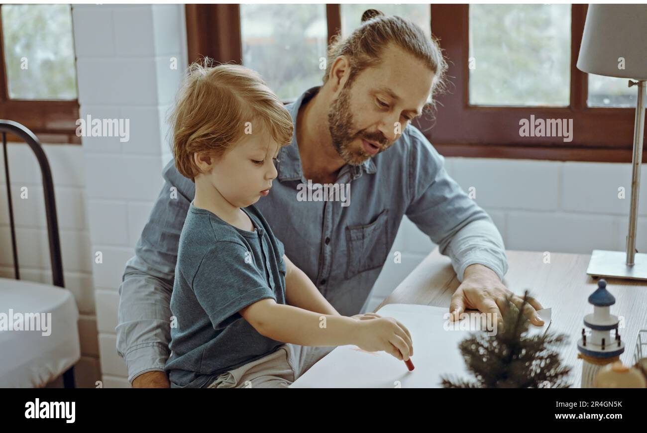 Caucasian family painting on paper with son indoors in house. Little ...