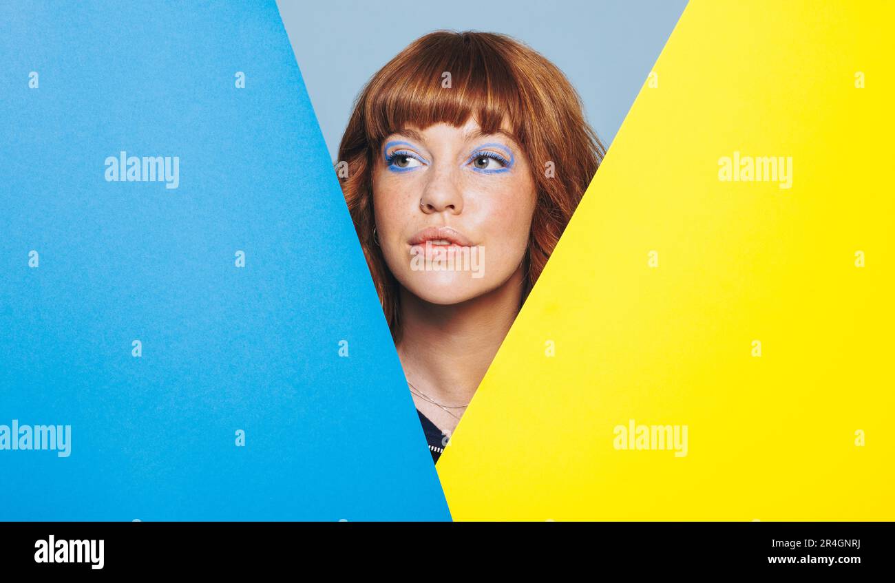 Woman standing behind colourful geometric shapes in an art studio ...