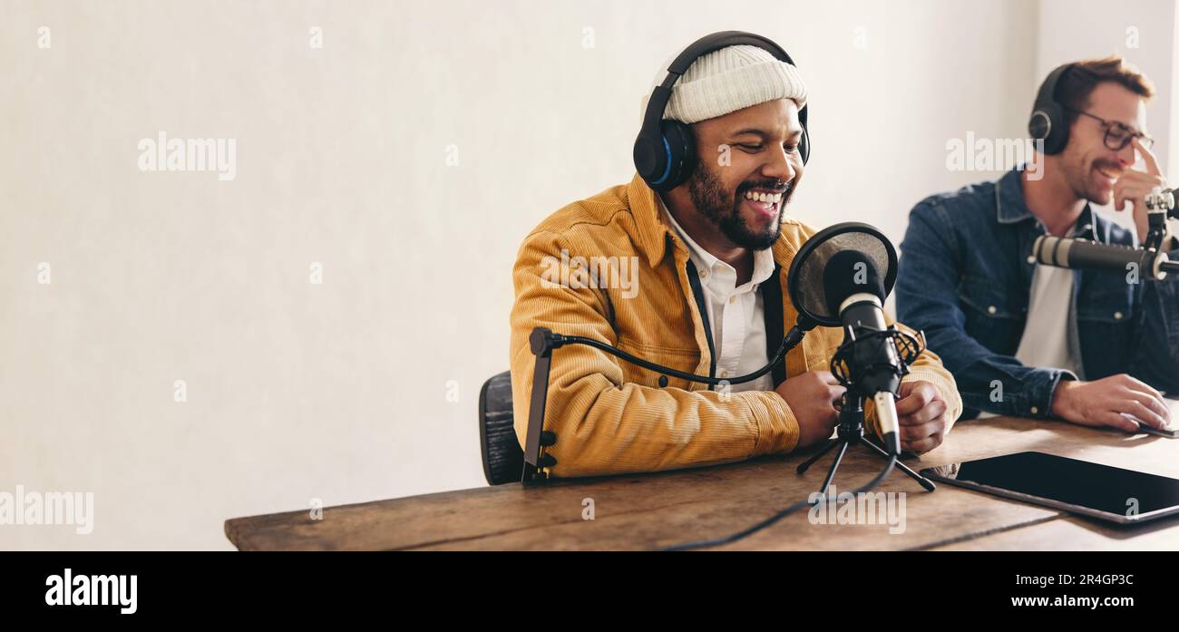 College radio dj smiling while speaking into a microphone in a studio ...
