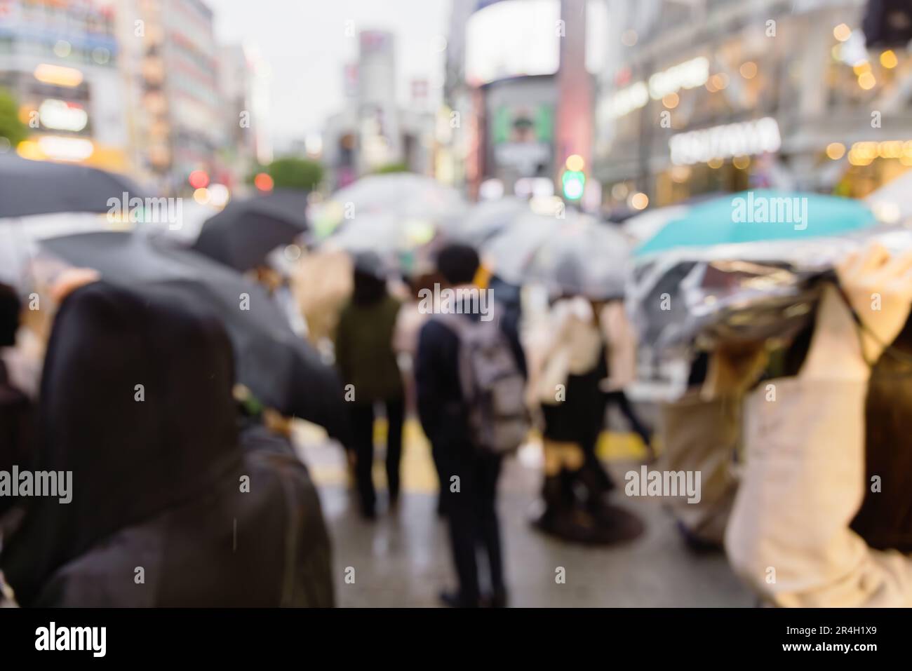 out of focus picture of a crowd of people with umbrellas crossing a ...