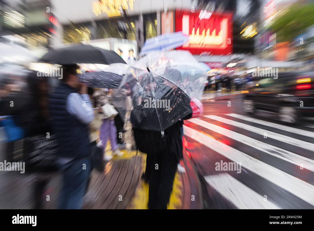 picture with zoom effect of a crowd of people with umbrellas crossing ...