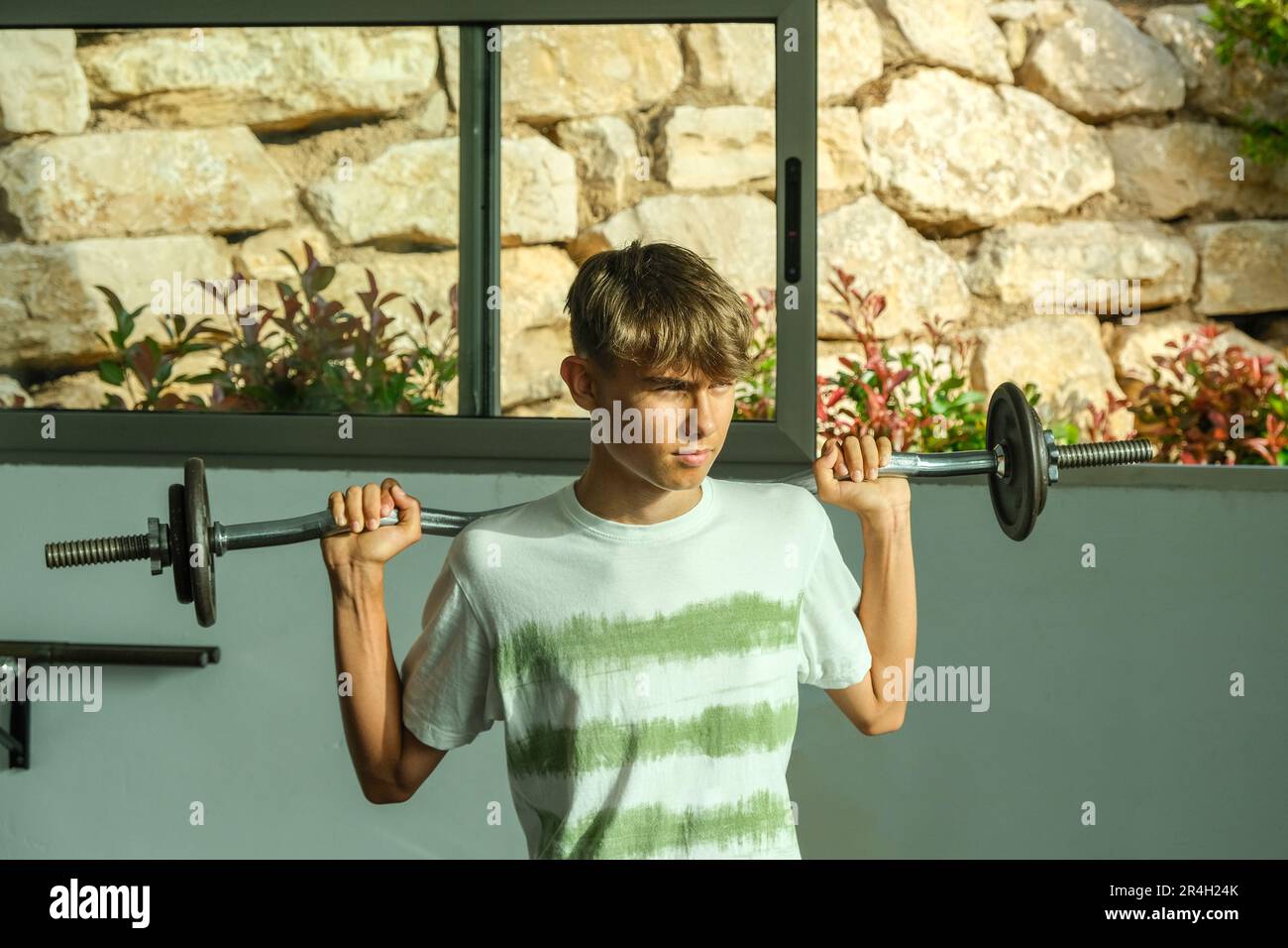 Teenage boy lifting barbell at home gym. Sport, strenght, training ...
