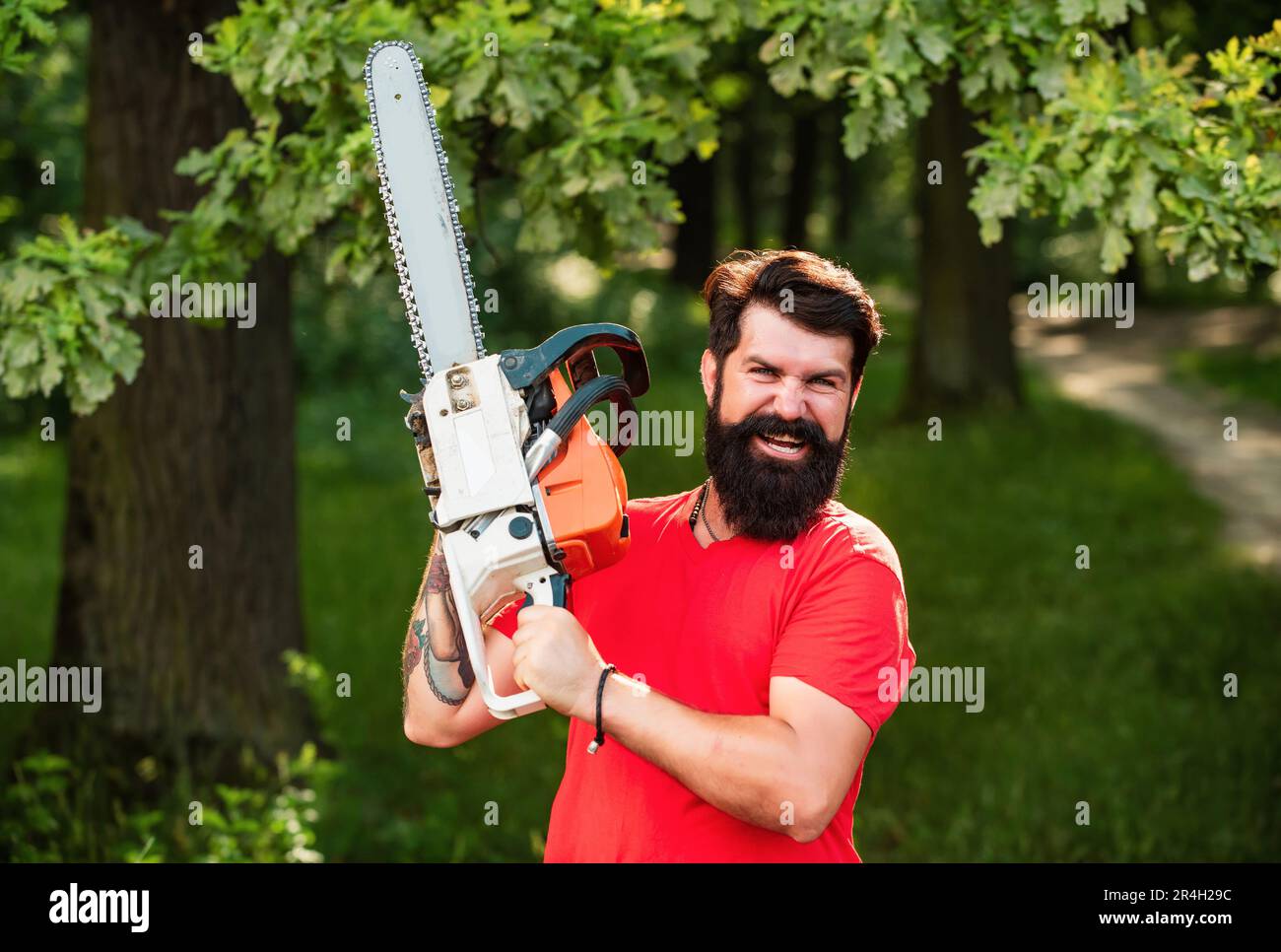 Lumberjack with chainsaw on forest background. Lumberjack holding the ...
