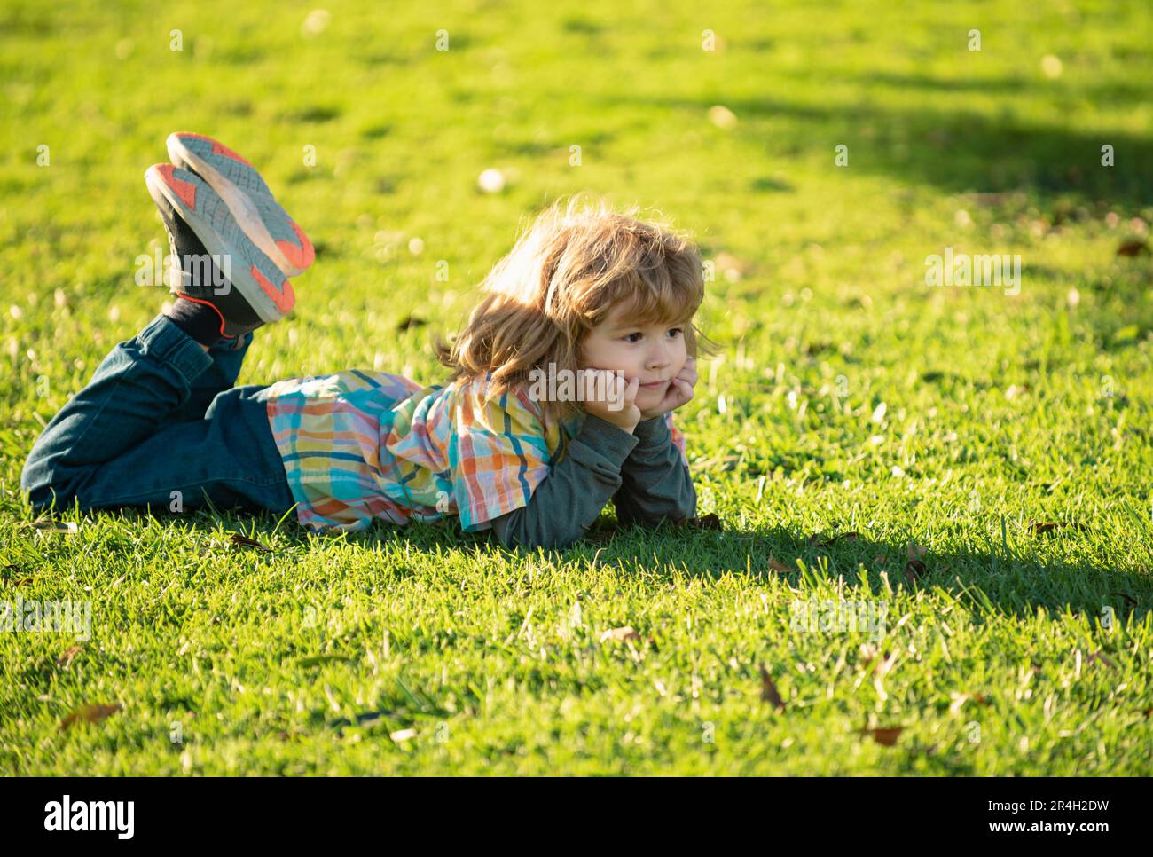 Child outdoor in park. Spring kid lying on grass. Summer boy walk ...
