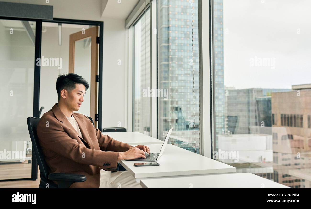 Young Asian business man manager working on laptop in corporate office ...