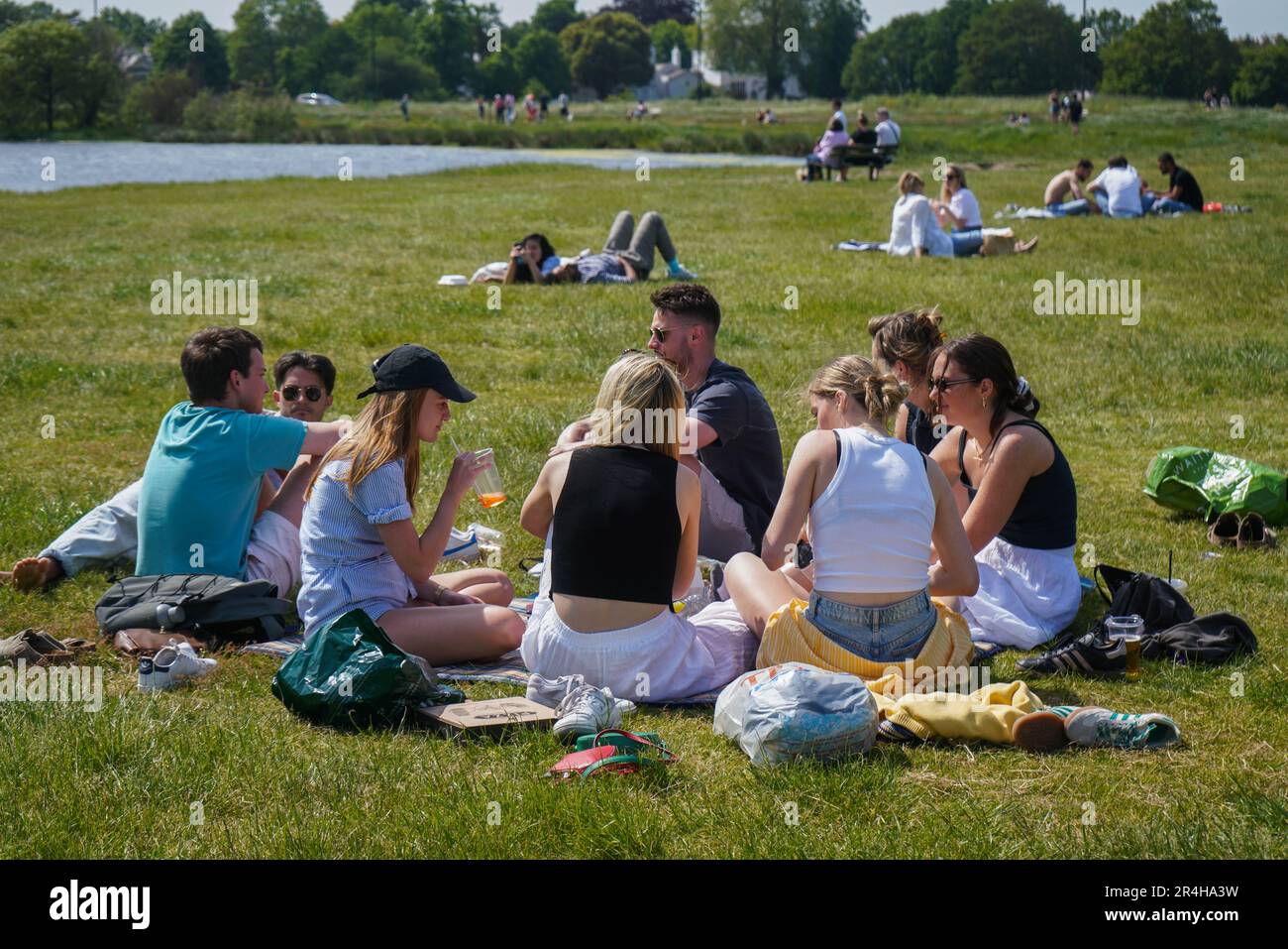 London UK. 28 May 2023 A group friends relaxing in the sunshine on ...