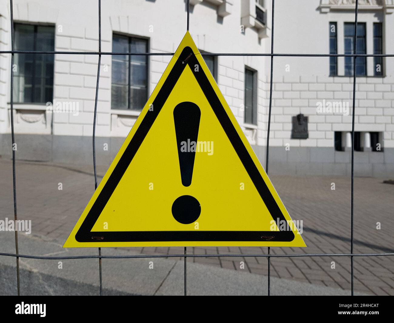 Warning triangle sign on a metal fence. Yellow exclamation mark on the ...