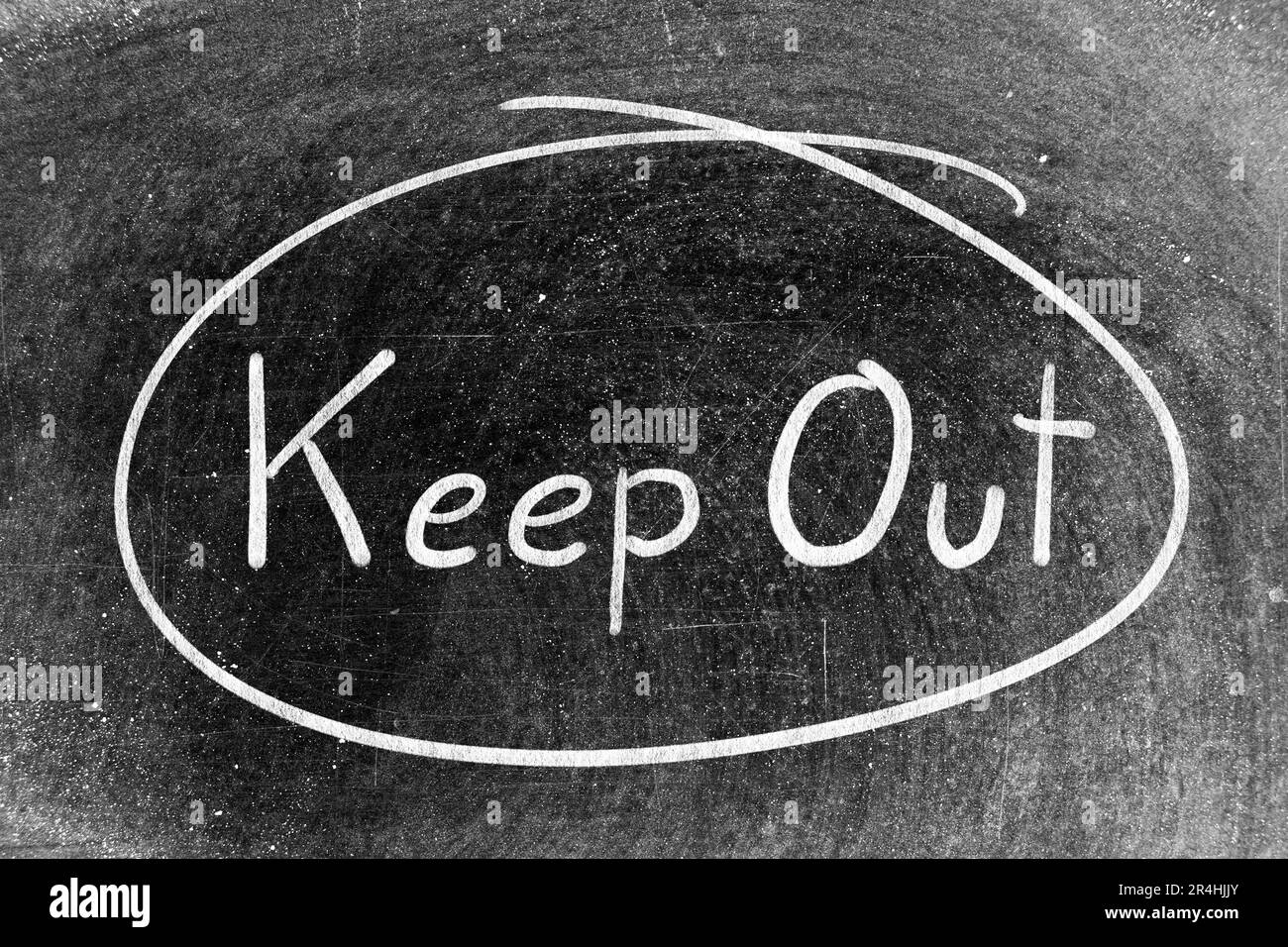 White chalk hand writing in word keep out and circle shape on ...