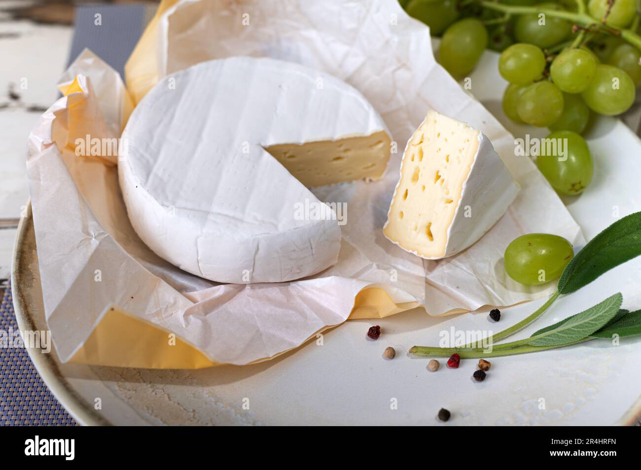 Camembert soft cheese on the plate with grapes and herbs Stock Photo ...