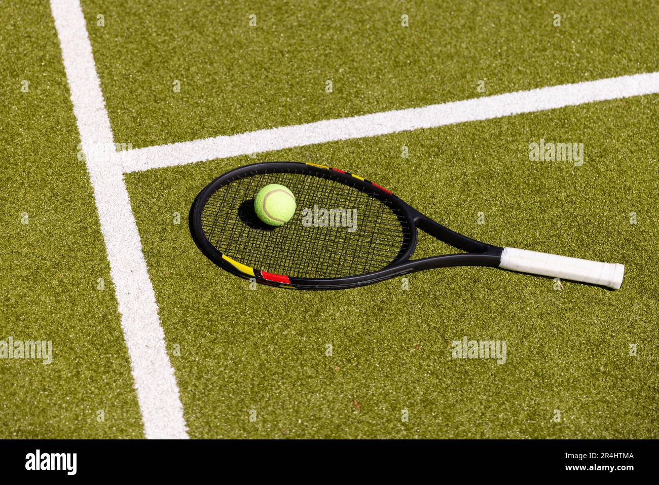 High angle view of tennis racket and ball by white marking on grassy ...