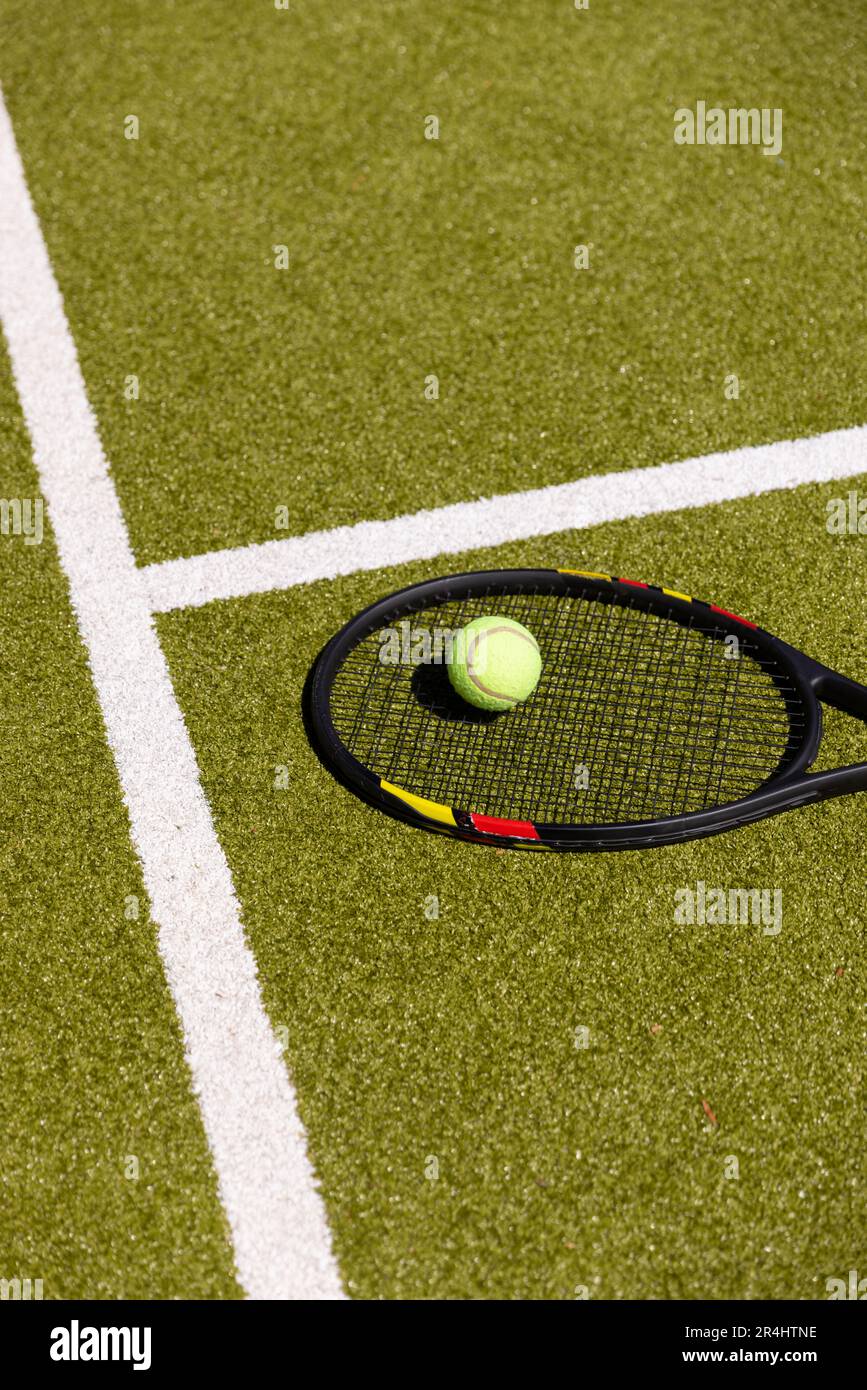 High angle view of tennis racket with ball by white marking on grassy ...