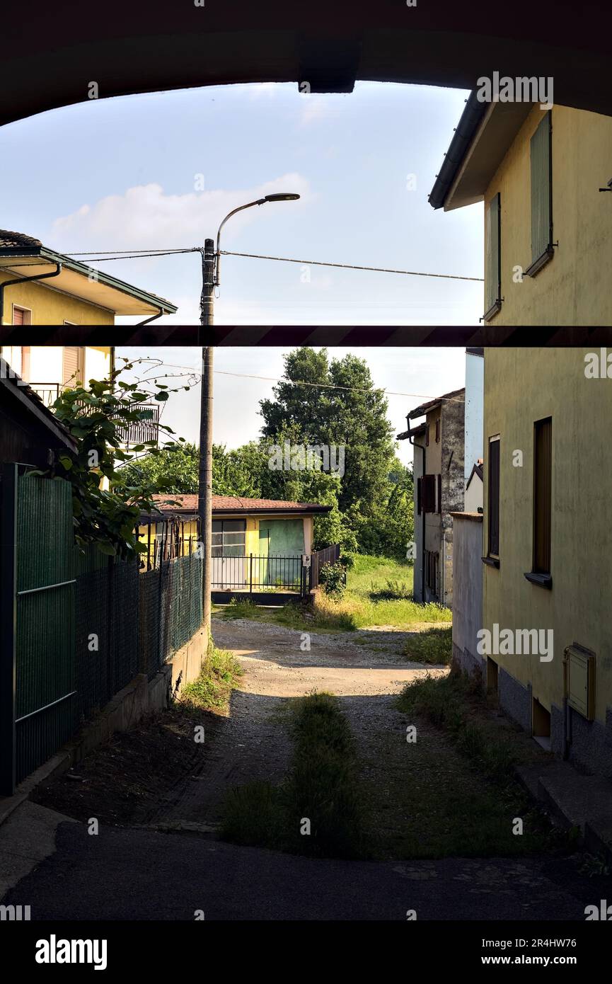Covered alley between buildings that leads to a path next to a field on ...
