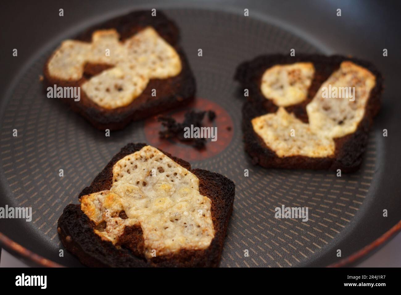 Three cheese sandwiches burned in the pan to black Stock Photo - Alamy