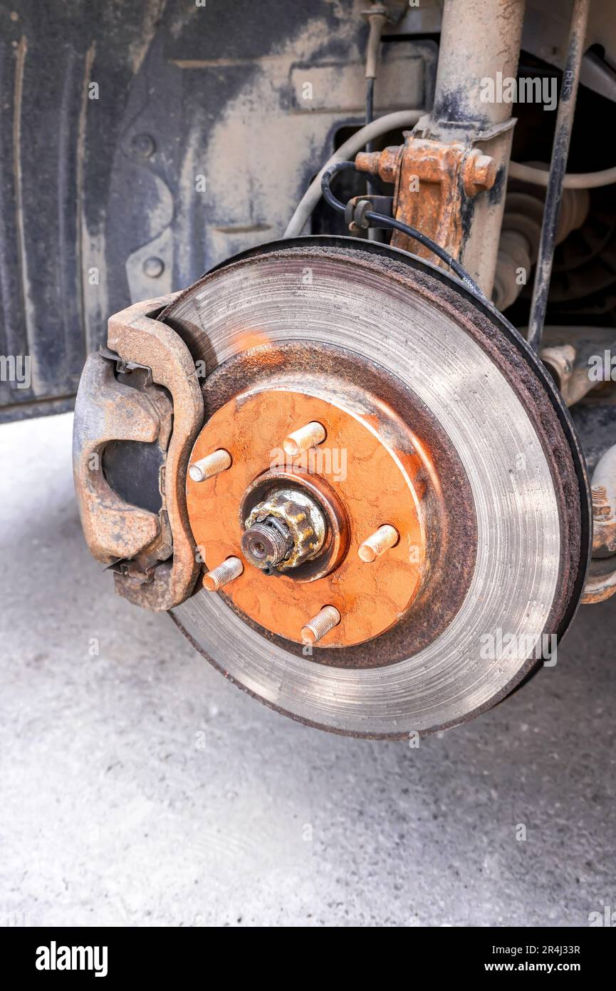 An old rusty car brake disc is lubricated with copper grease before ...