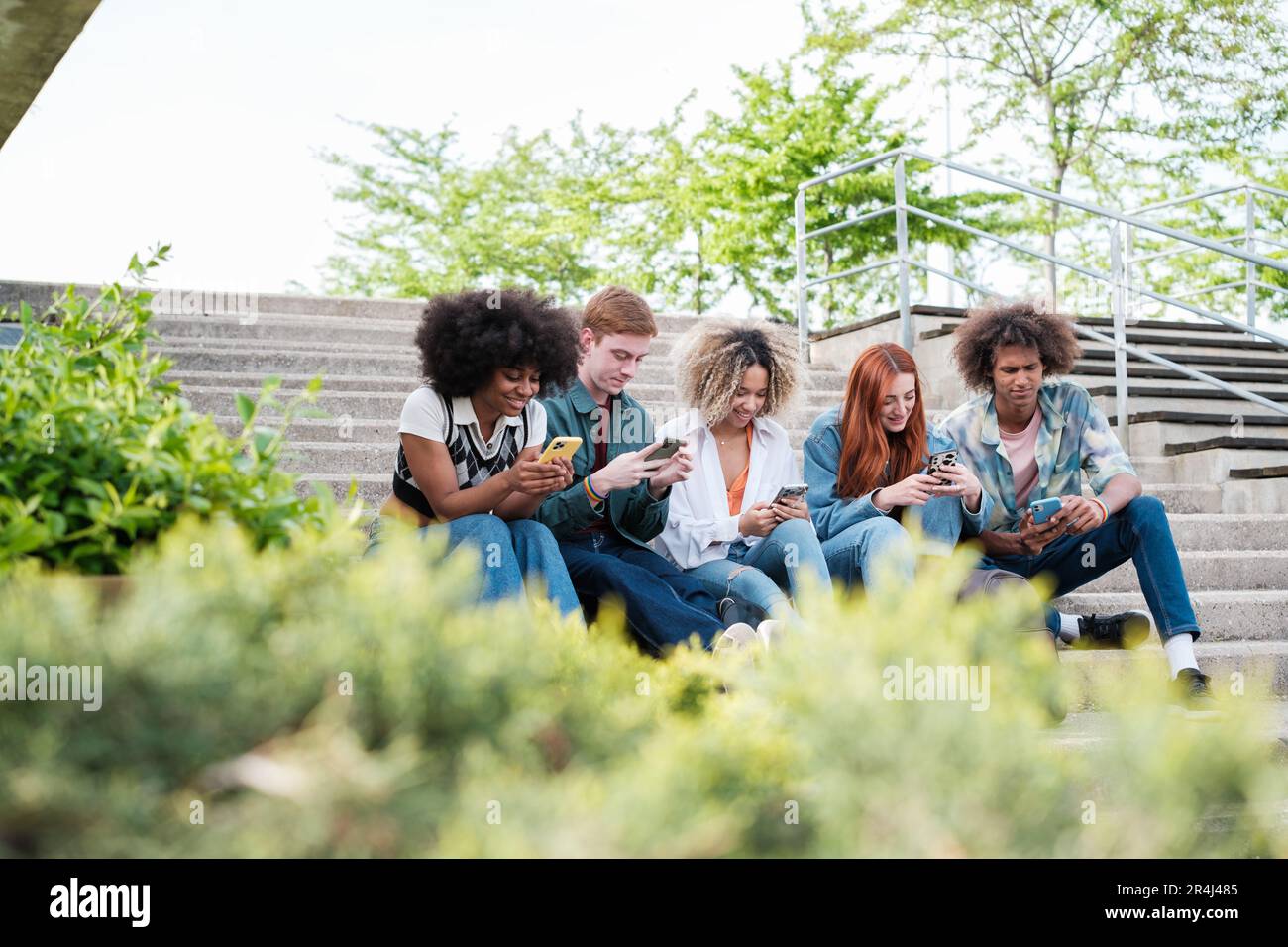 Group of students sitting around the university campus looking only at ...