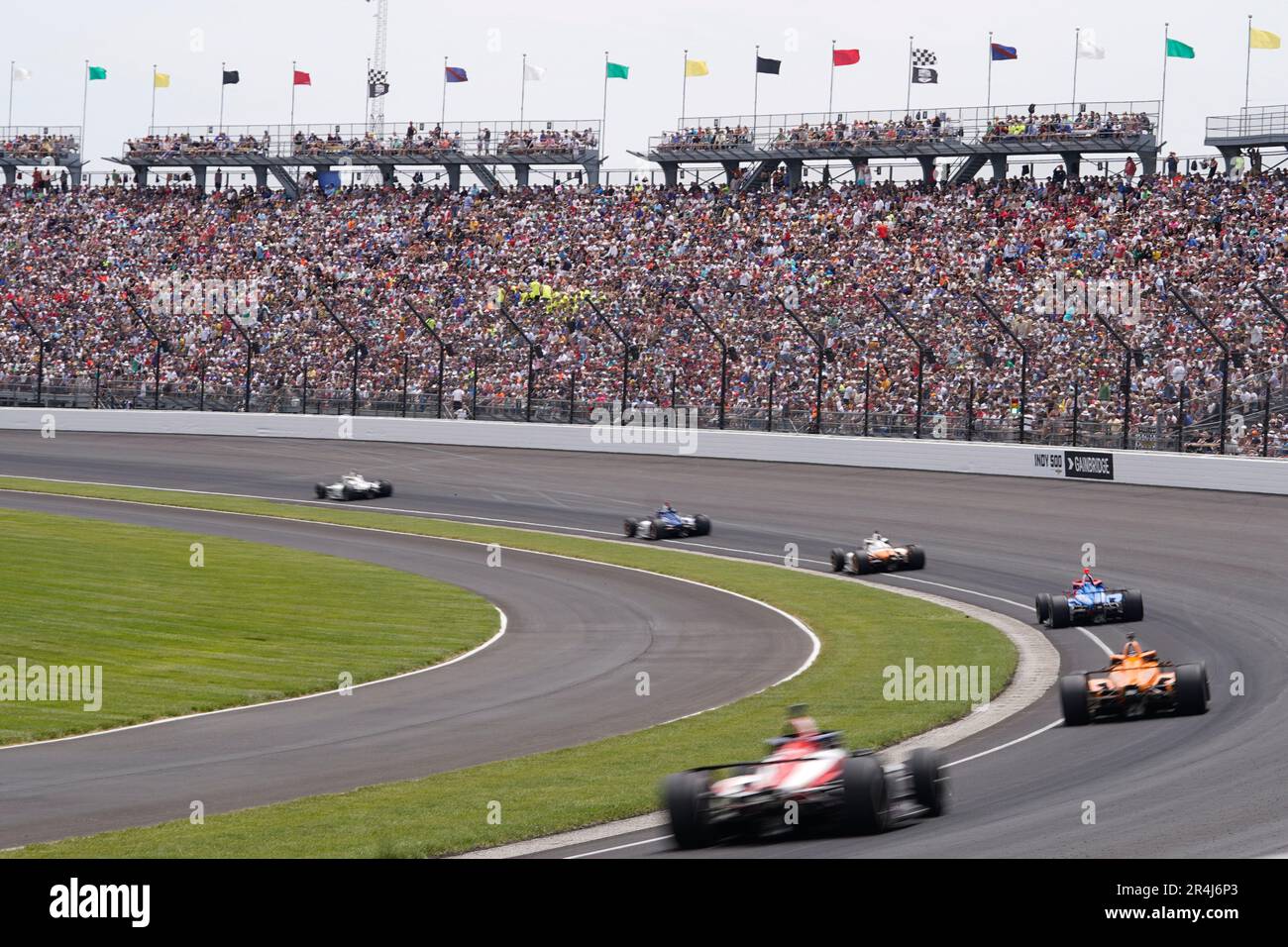 Race fans watch as cars go through the first turn during the ...