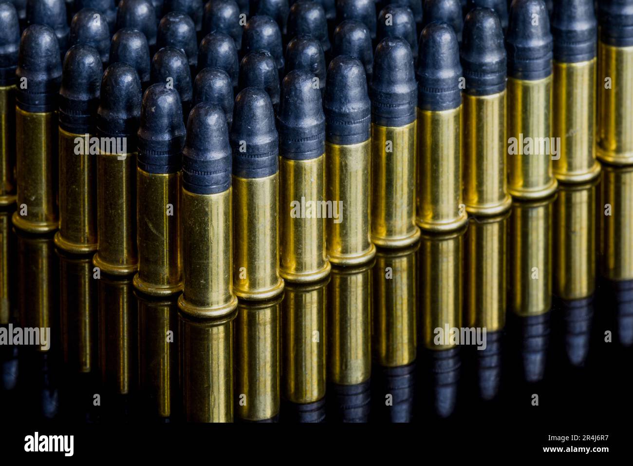 Many small caliber bullets lined up. With reflection on a black ...