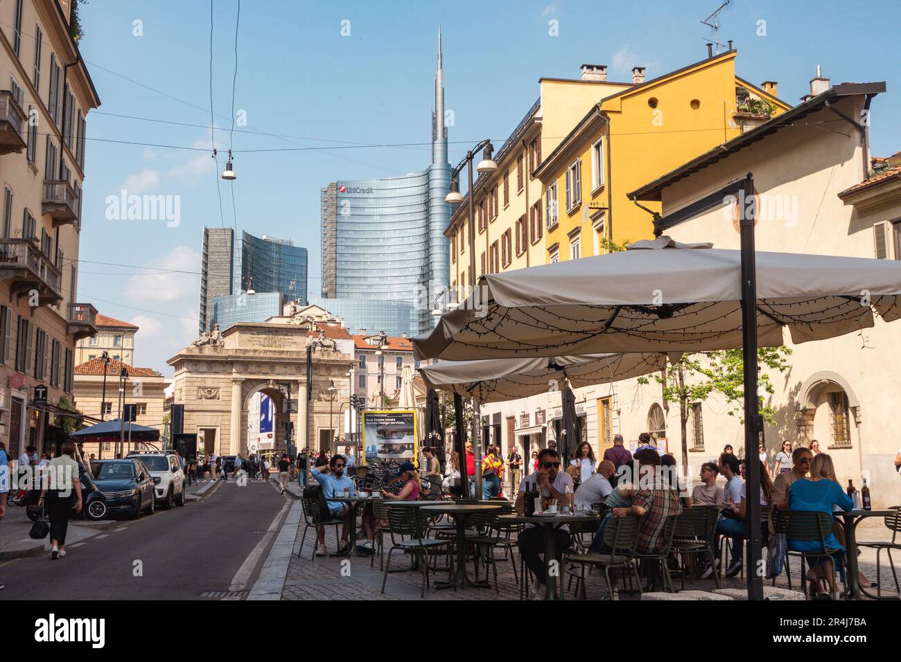 Street in Milan, people sitting outdoors, cafe tables in summer ...