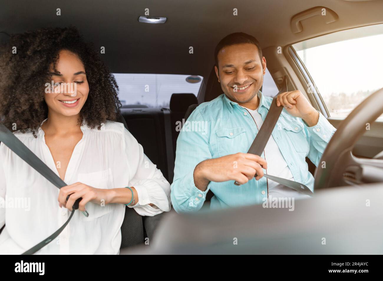 Couple practicing safe driving habits wearing seat belts in car Stock ...
