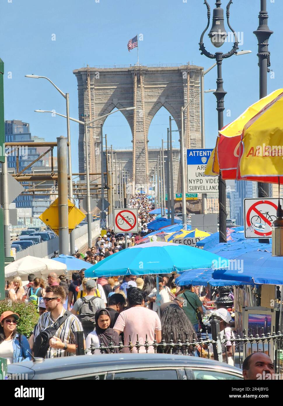 Crowds of tourists flock across The Brooklyn Bridge is a hybrid cable ...