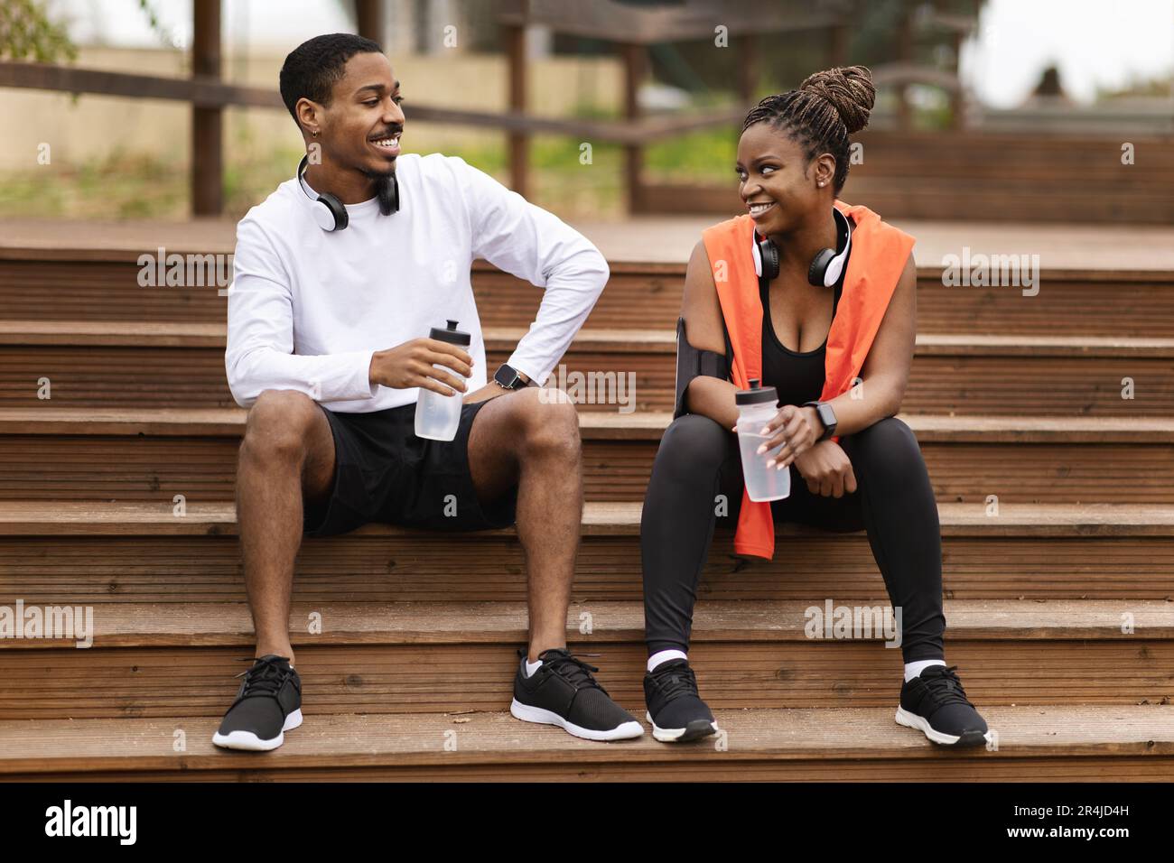 Cheerful young black couple sitting on stairs, talking, relaxing with ...