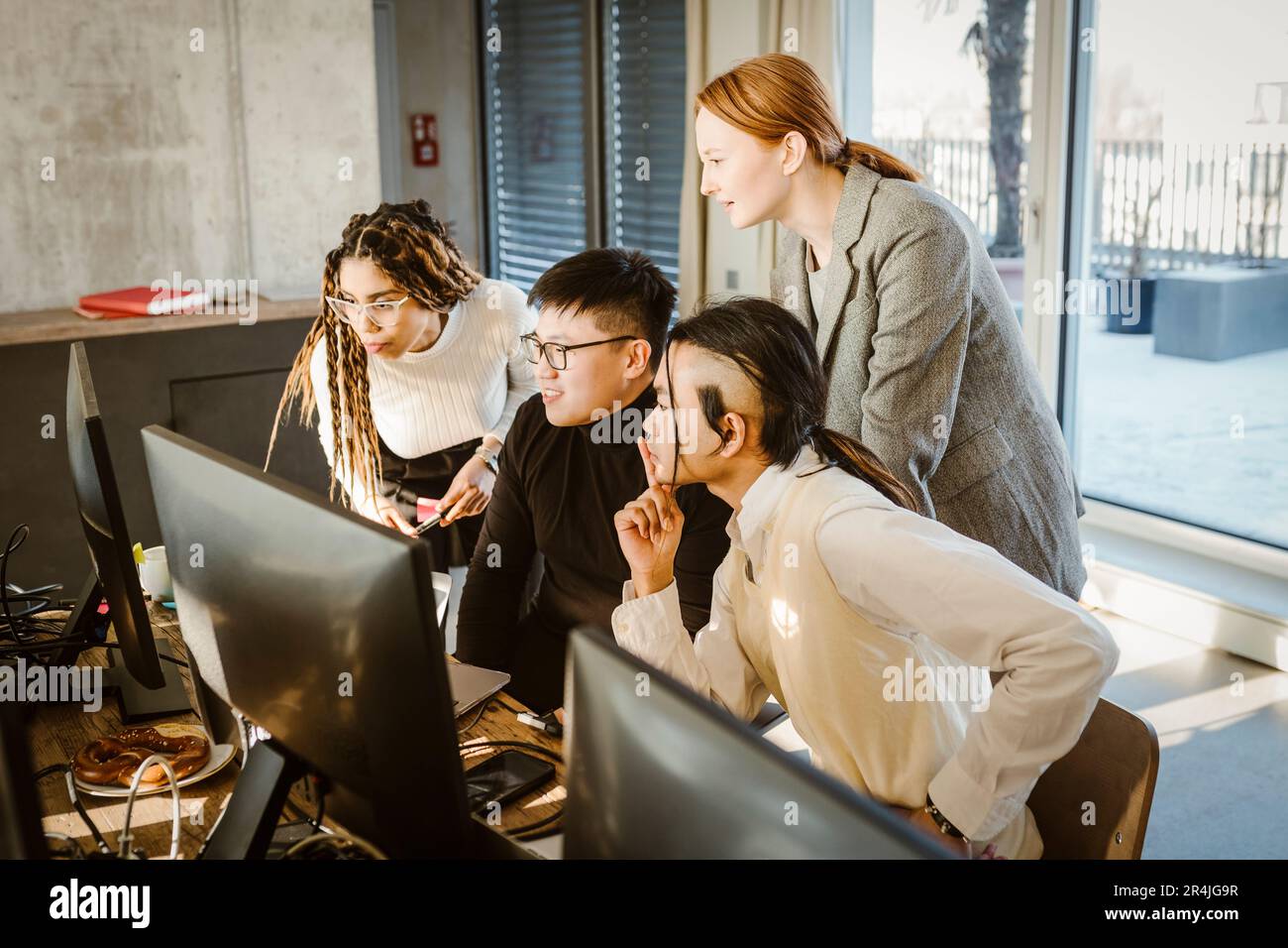 Multiracial male and female programmers discussing over computer in ...