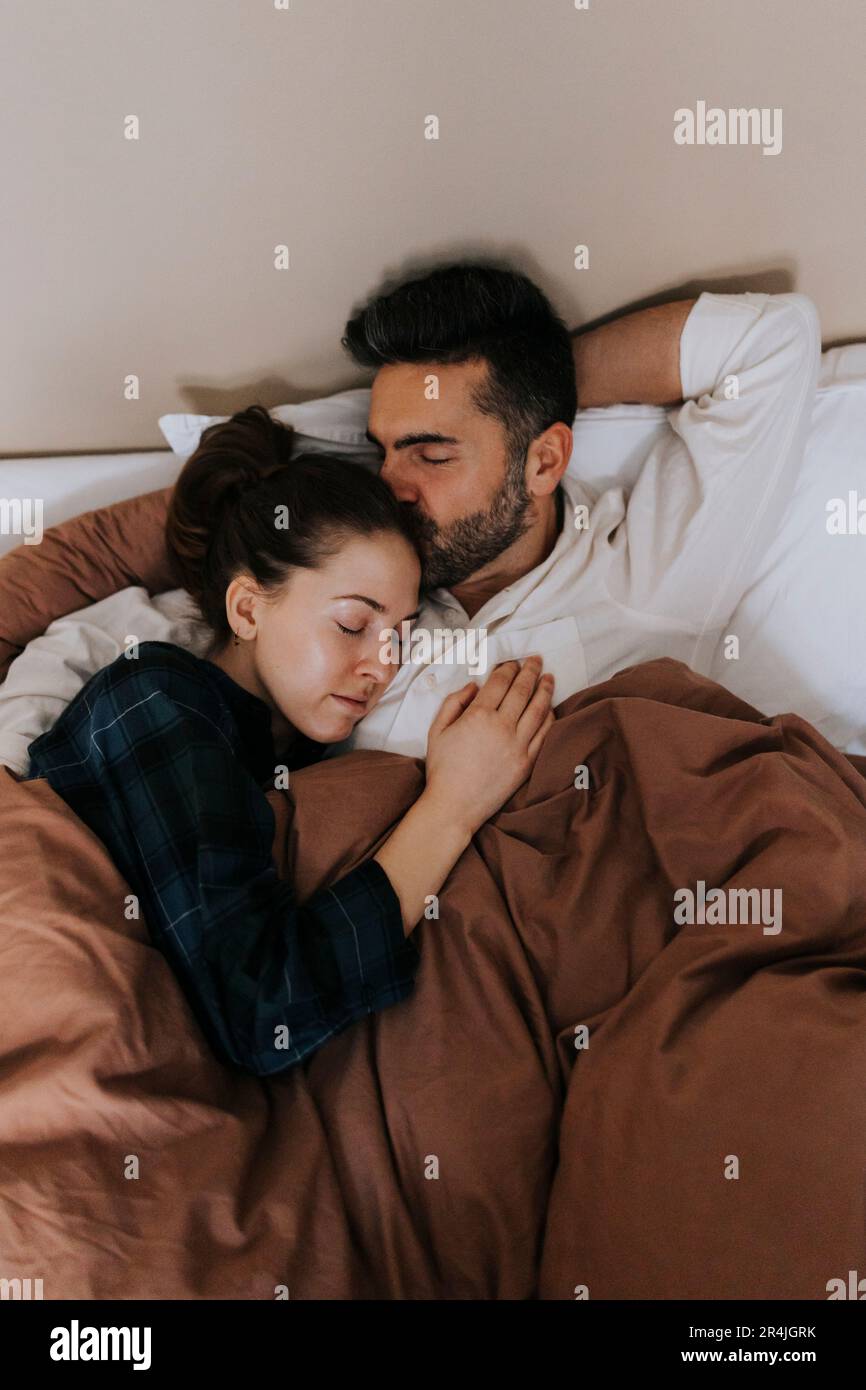 High angle view of man kissing non-binary person relaxing in bed at home Stock Photo - Alamy