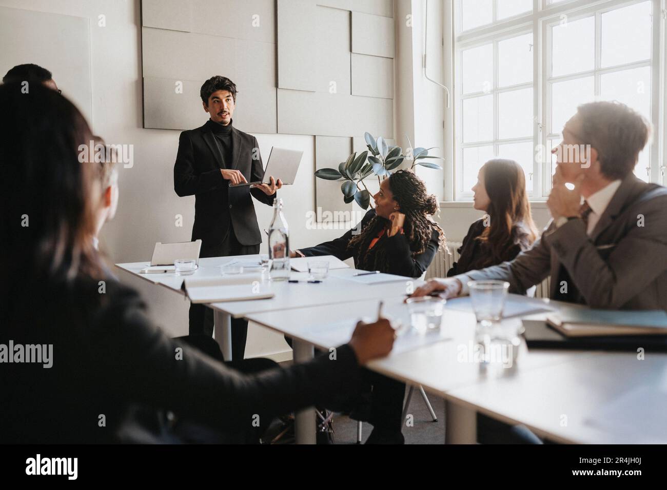 Male entrepreneur conducting business meeting with team in board room ...