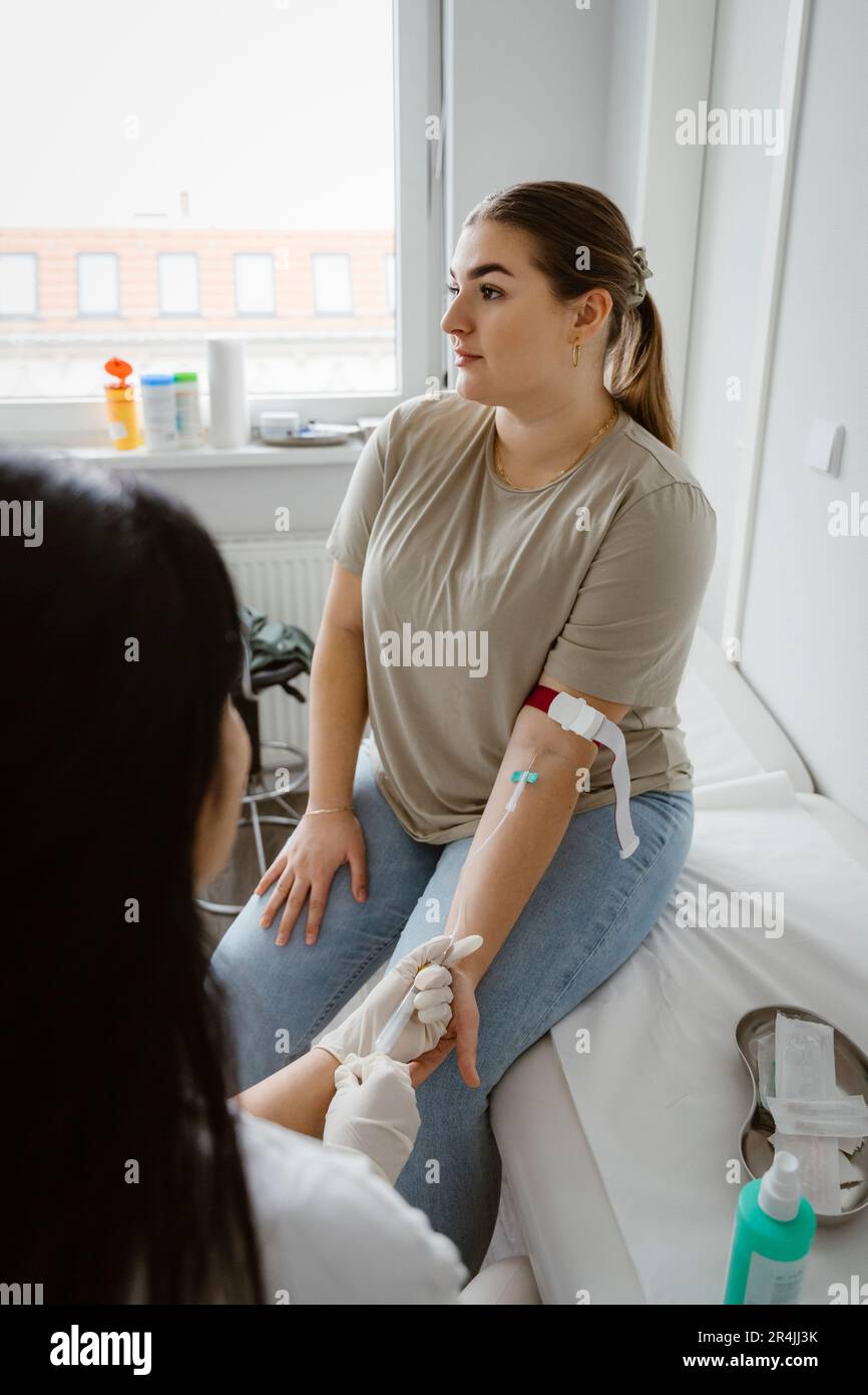Female patient doing medical checkup while sitting on bed in clinic Stock Photo - Alamy
