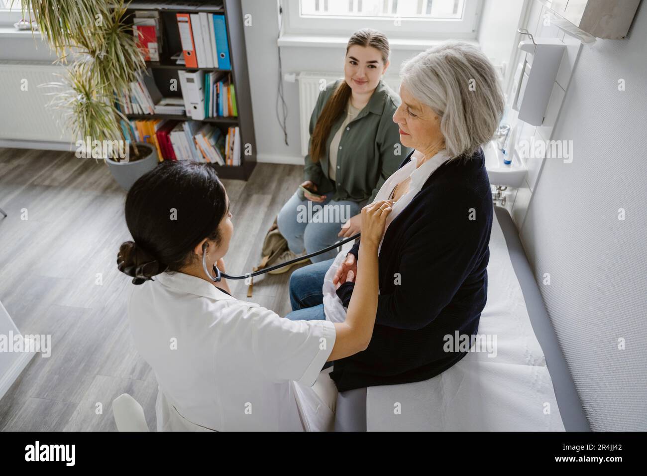 High angle view of female doctor listening heartbeat of senior patient ...