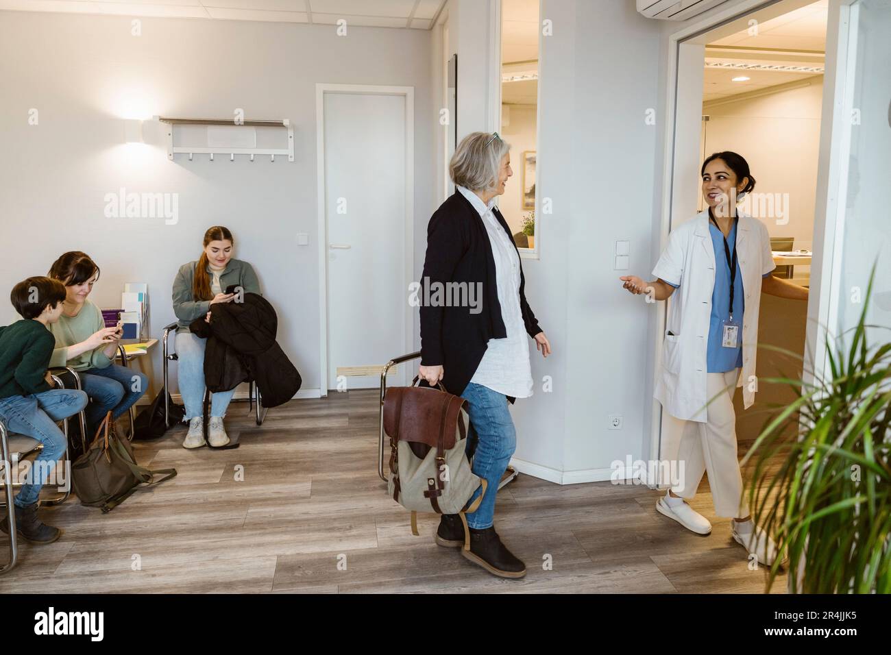 Senior female patient walking towards medical examination room with ...