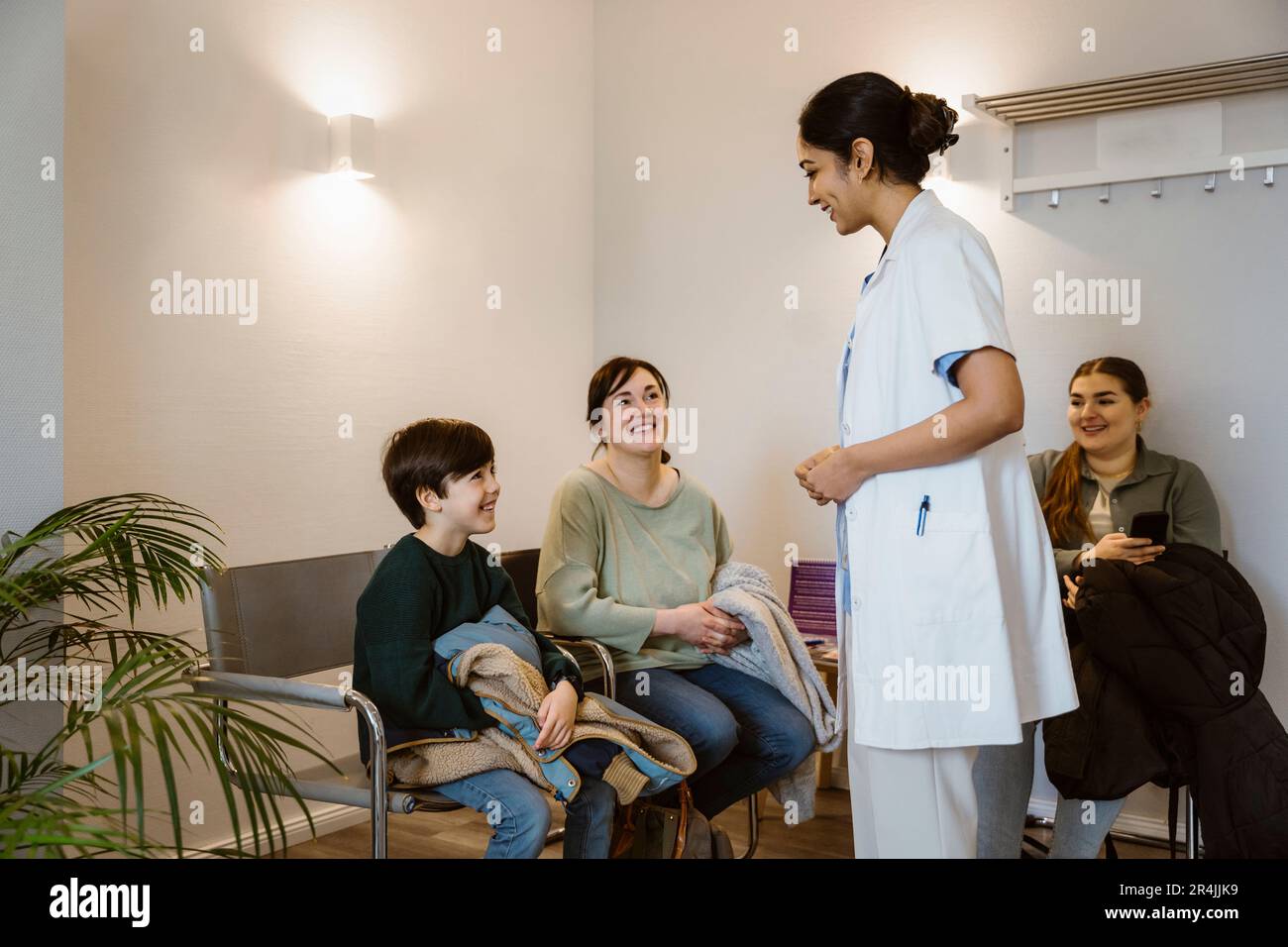 Side view of female healthcare worker wearing lab coat talking to boy ...
