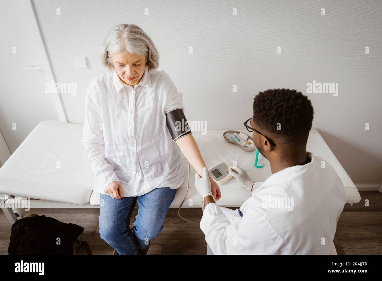 High angle view of male doctor measuring blood pressure of senior ...