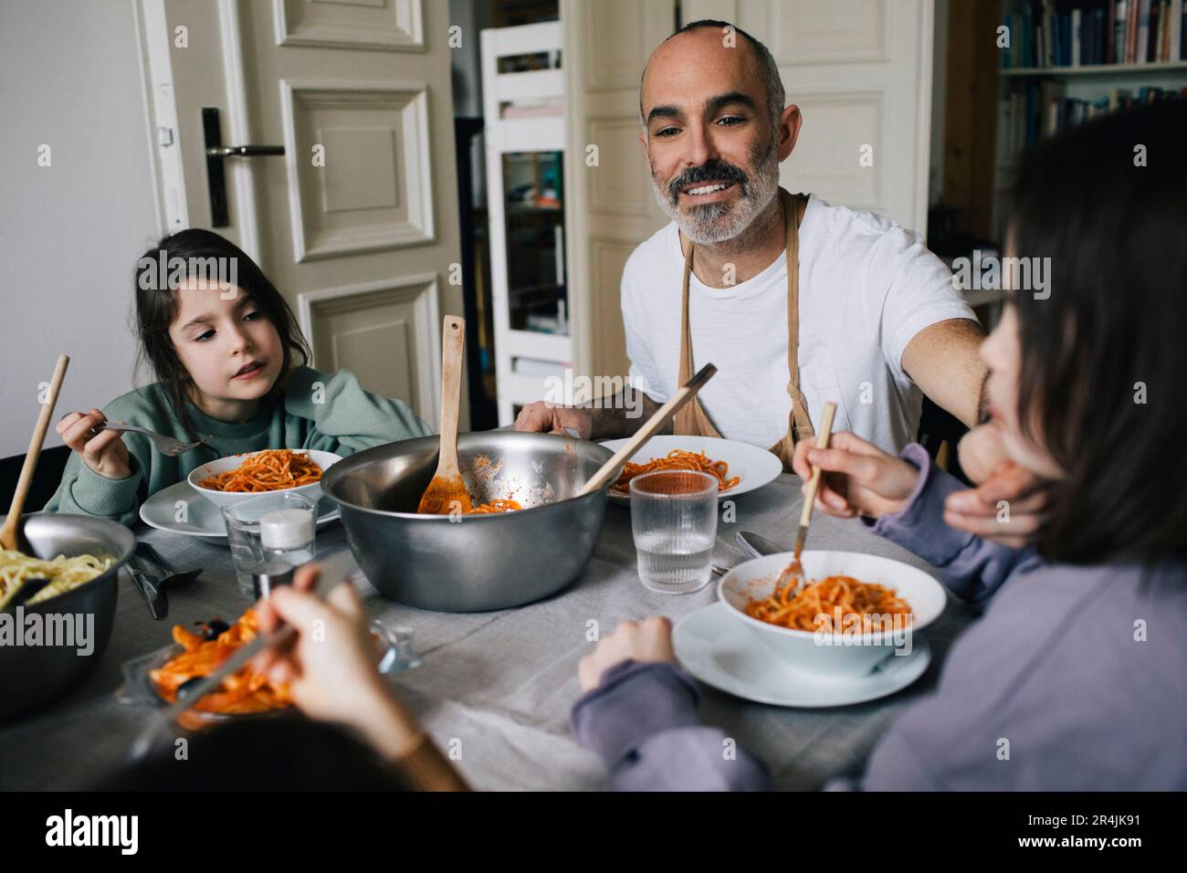 Happy father eating spaghetti with children at dining table Stock Photo ...