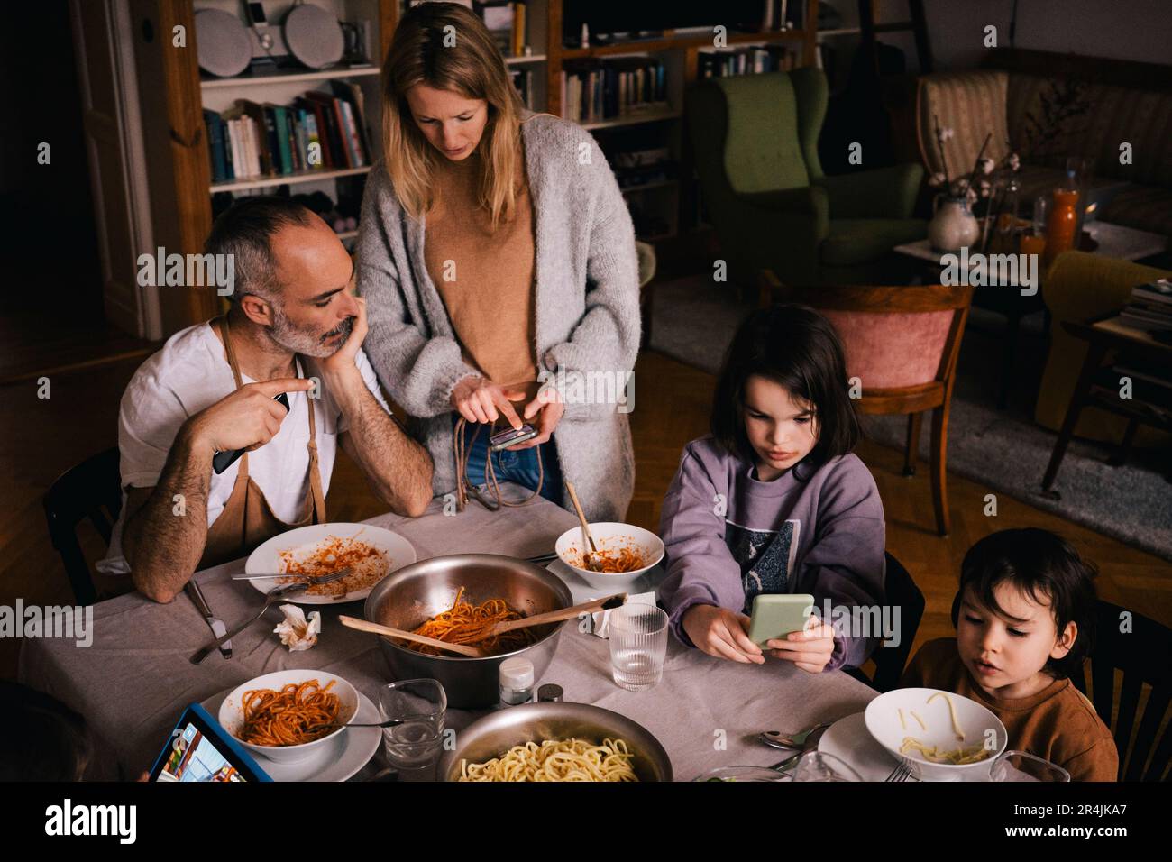 Family with spaghetti using smart phones at dining table Stock Photo ...