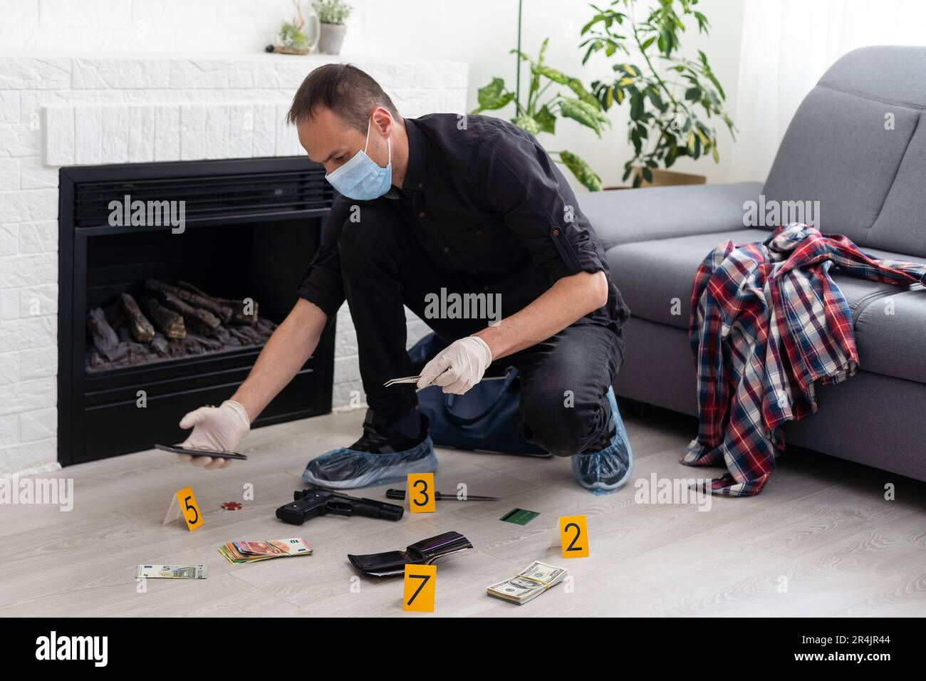 Young policeman collecting evidence standing behhind yellow crime scene ...