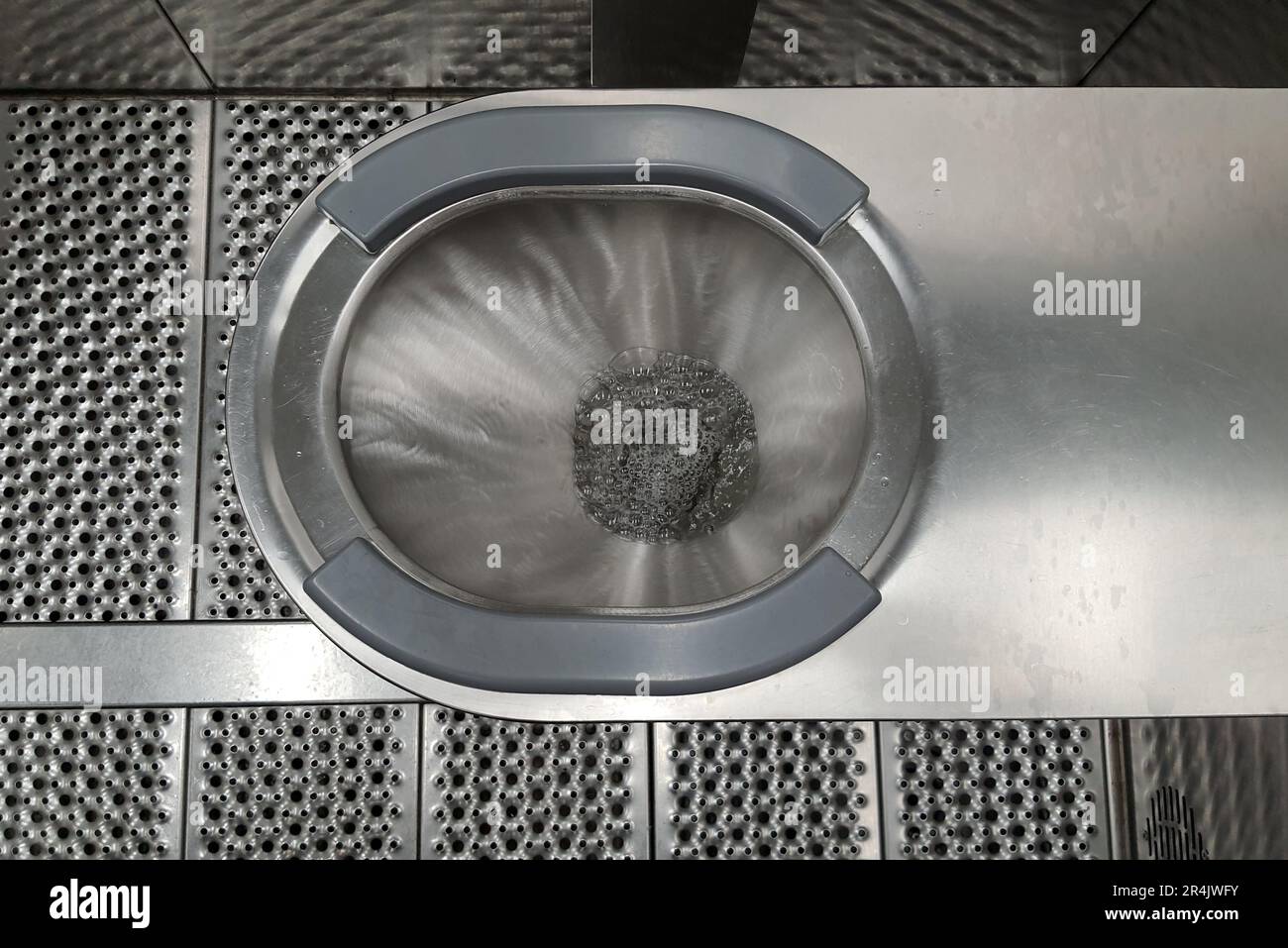 Sanitary metal urinal, toilet bowl in public bathroom with hygienic ...