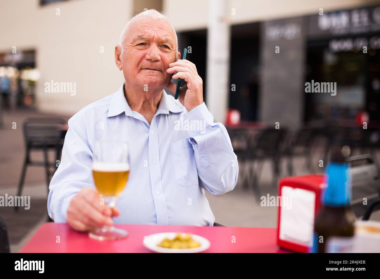 Old man having telephone conversation in outdoor cafe Stock Photo - Alamy
