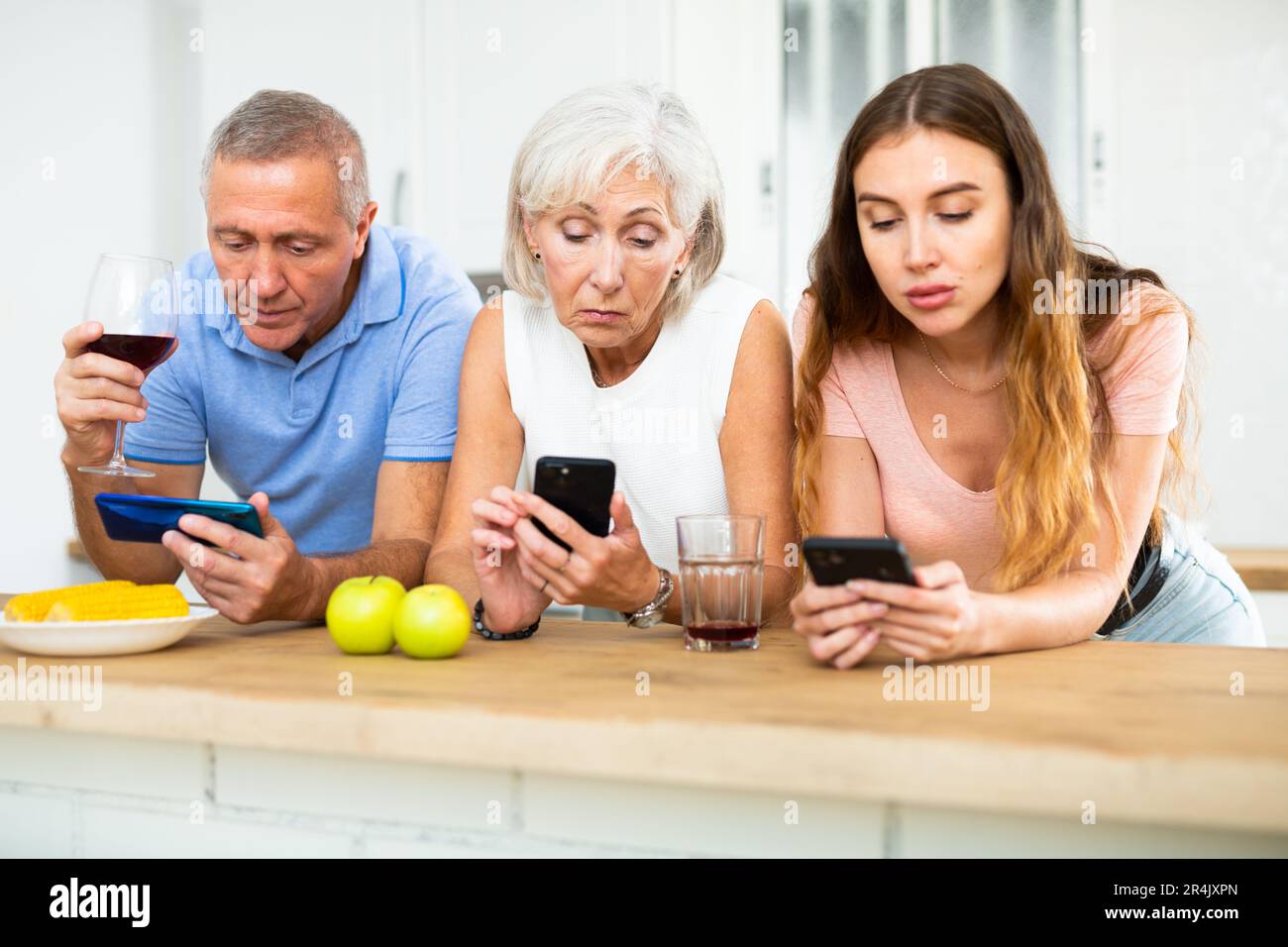 Family using gadgets whilst eating Stock Photo - Alamy